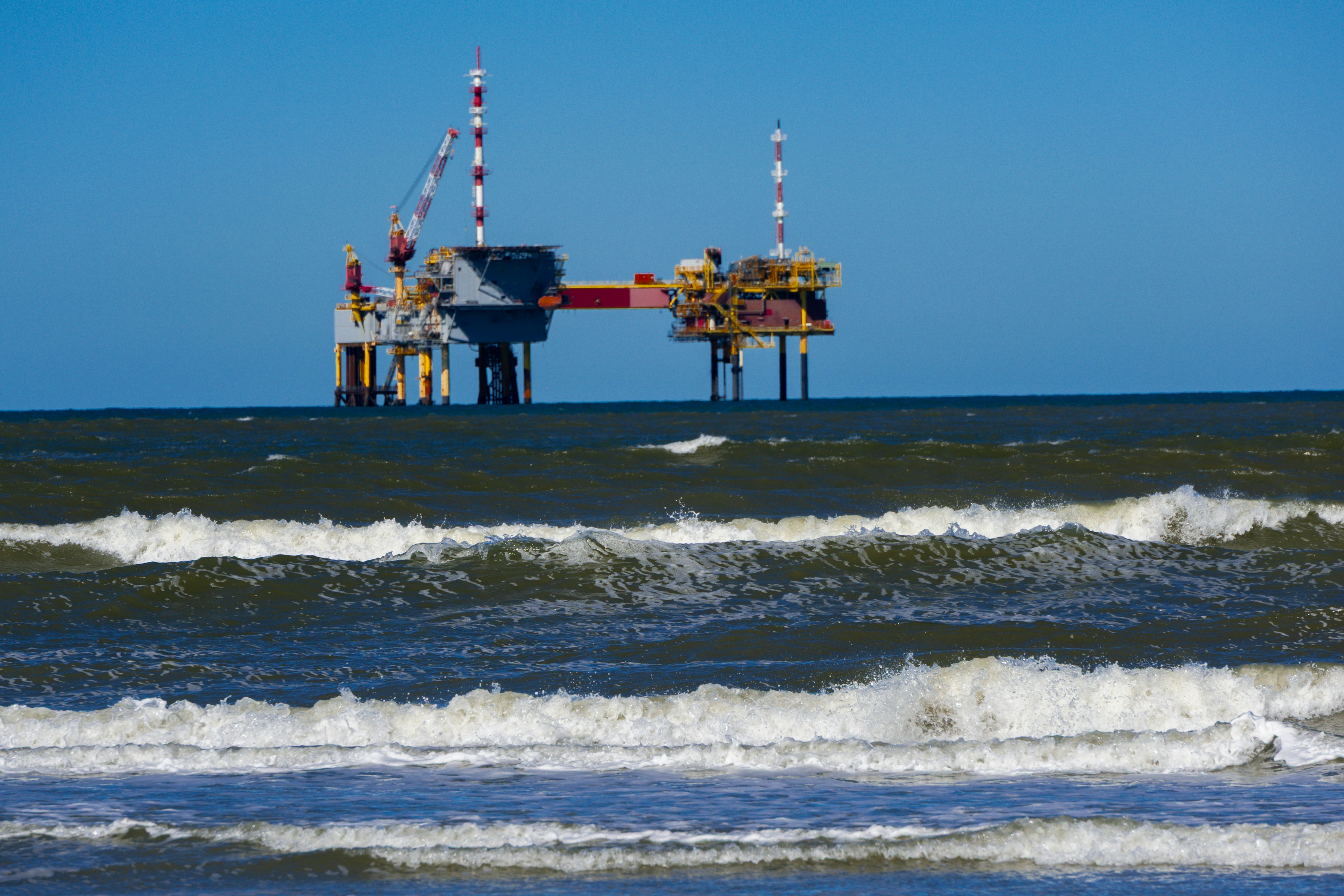 An oil platform in the ocean with breaking waves.