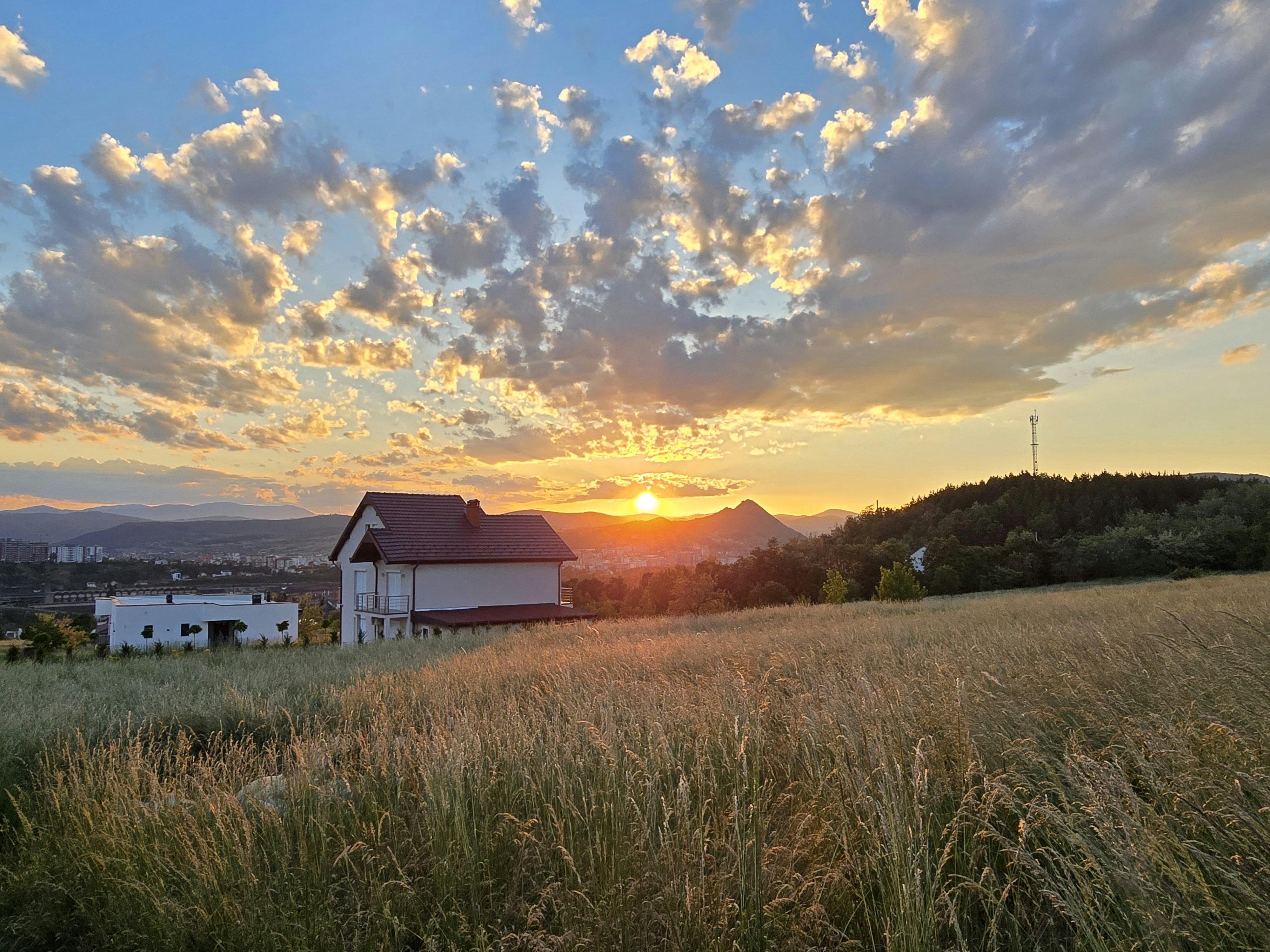 Golden Horizon Over Rolling Meadow and House