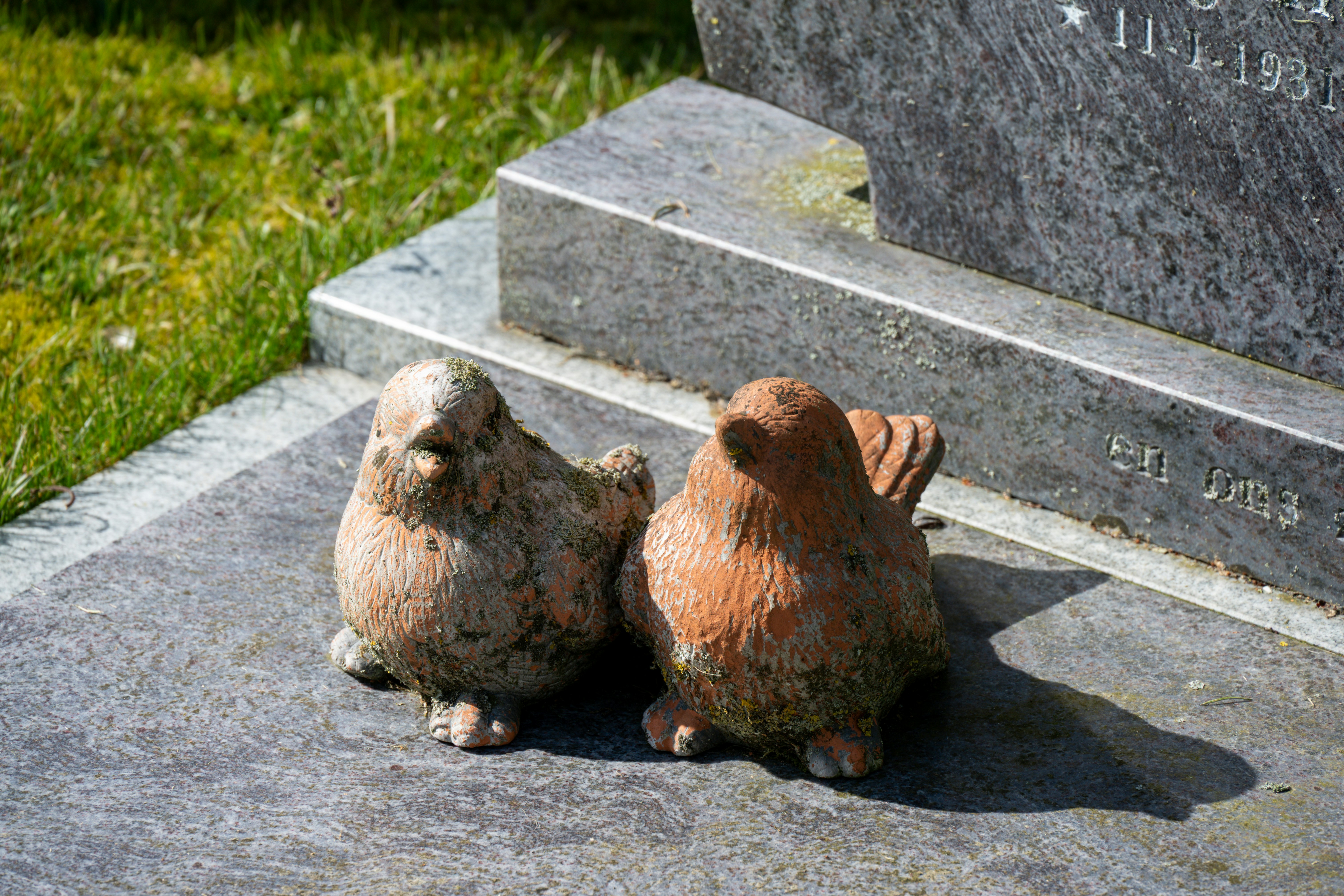 Two weathered bird sculptures guard a tombstone