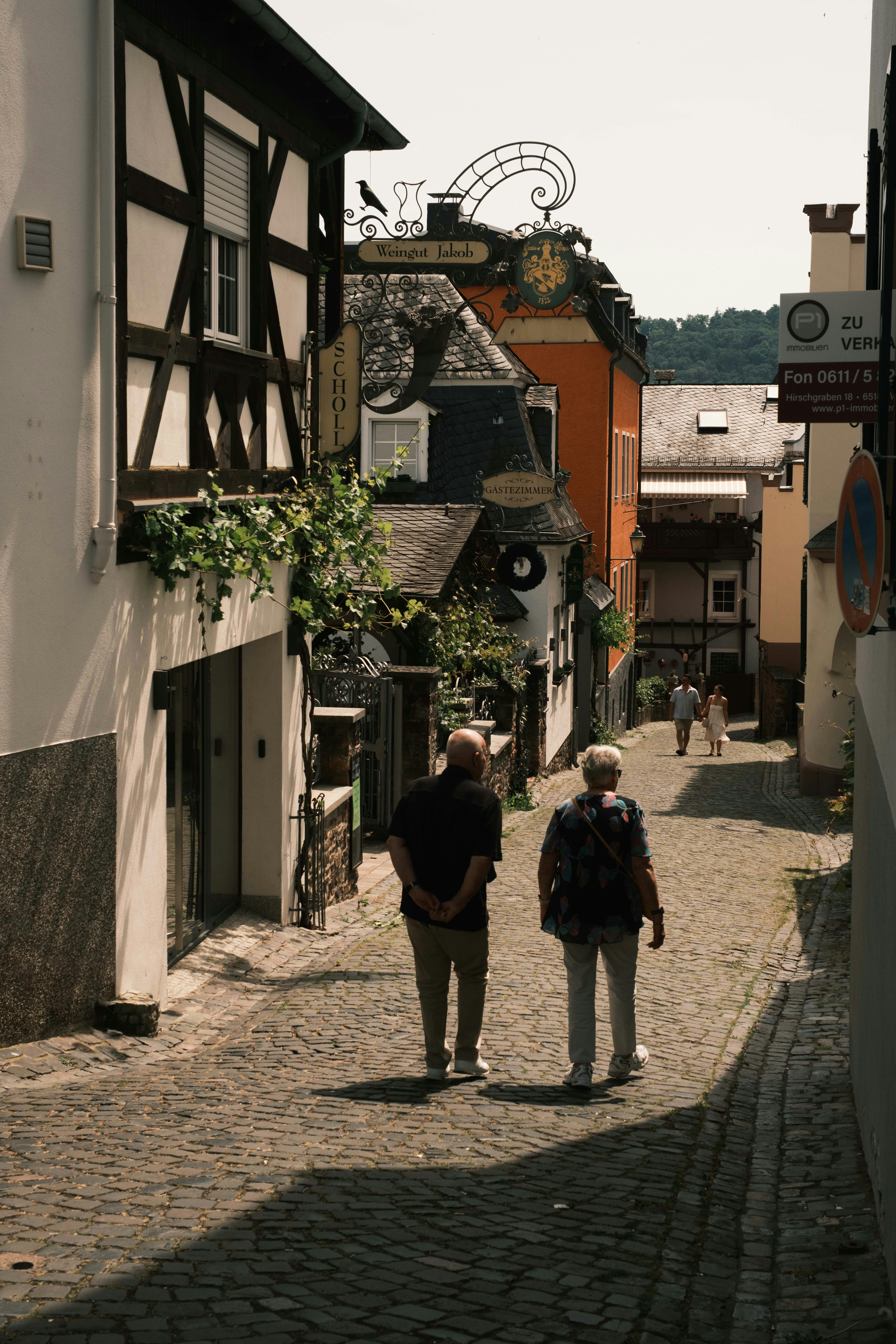 Two Walkers in a Sunlit German Cobblestone Alley