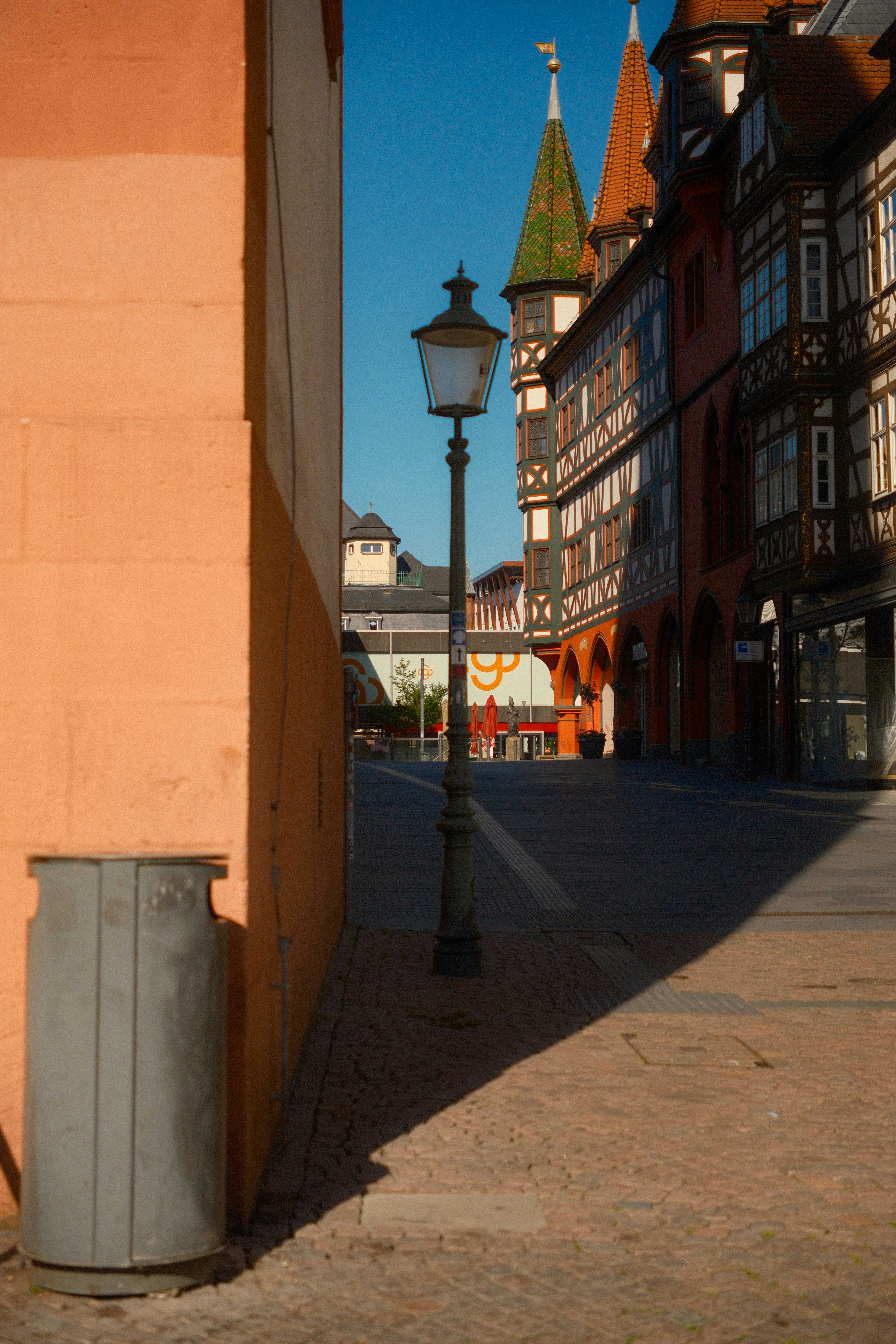 Sunlit Alleyway with Prominent Facades and Vintage Lamp Post