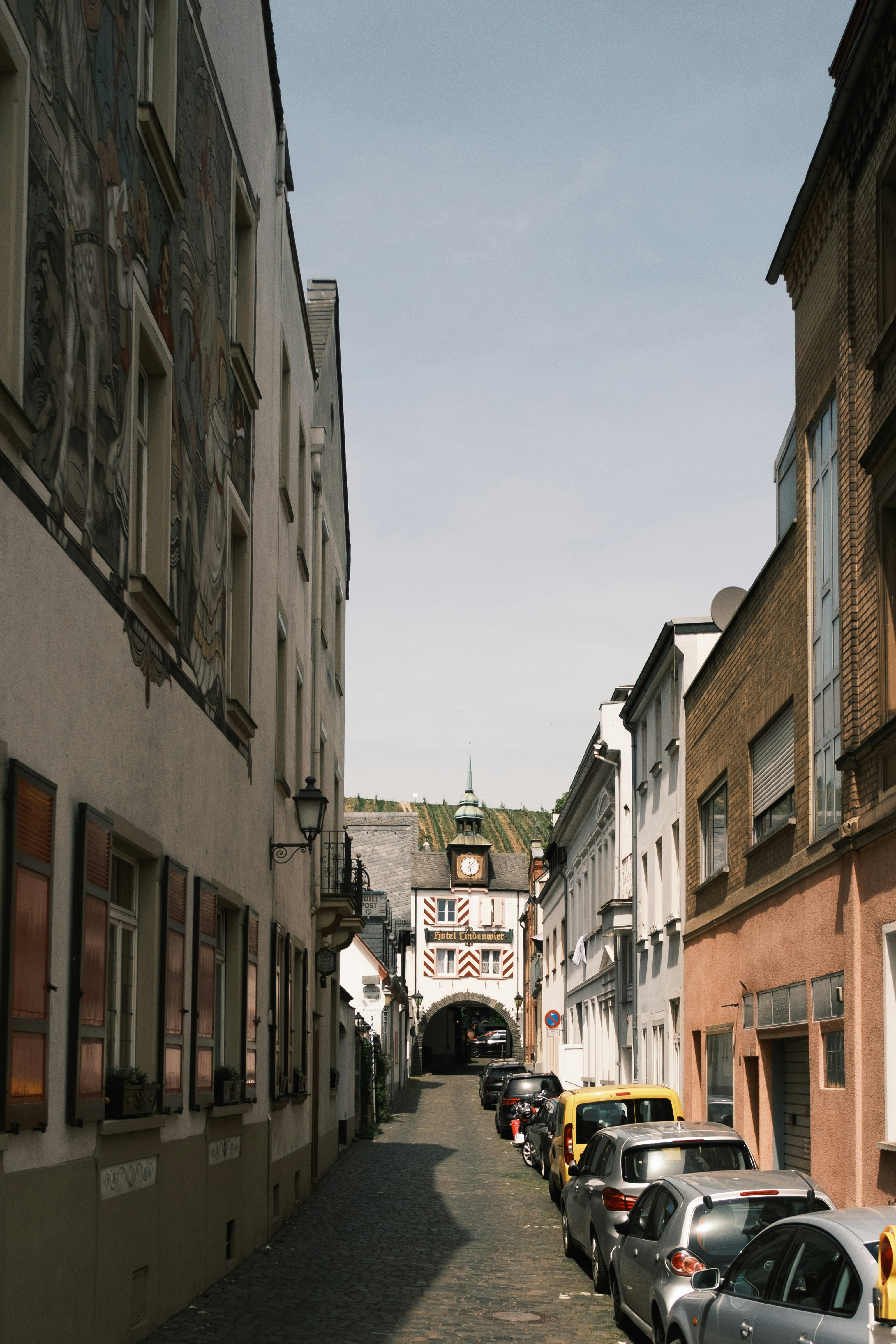 Cobblestone street lined with historic buildings and parked cars.