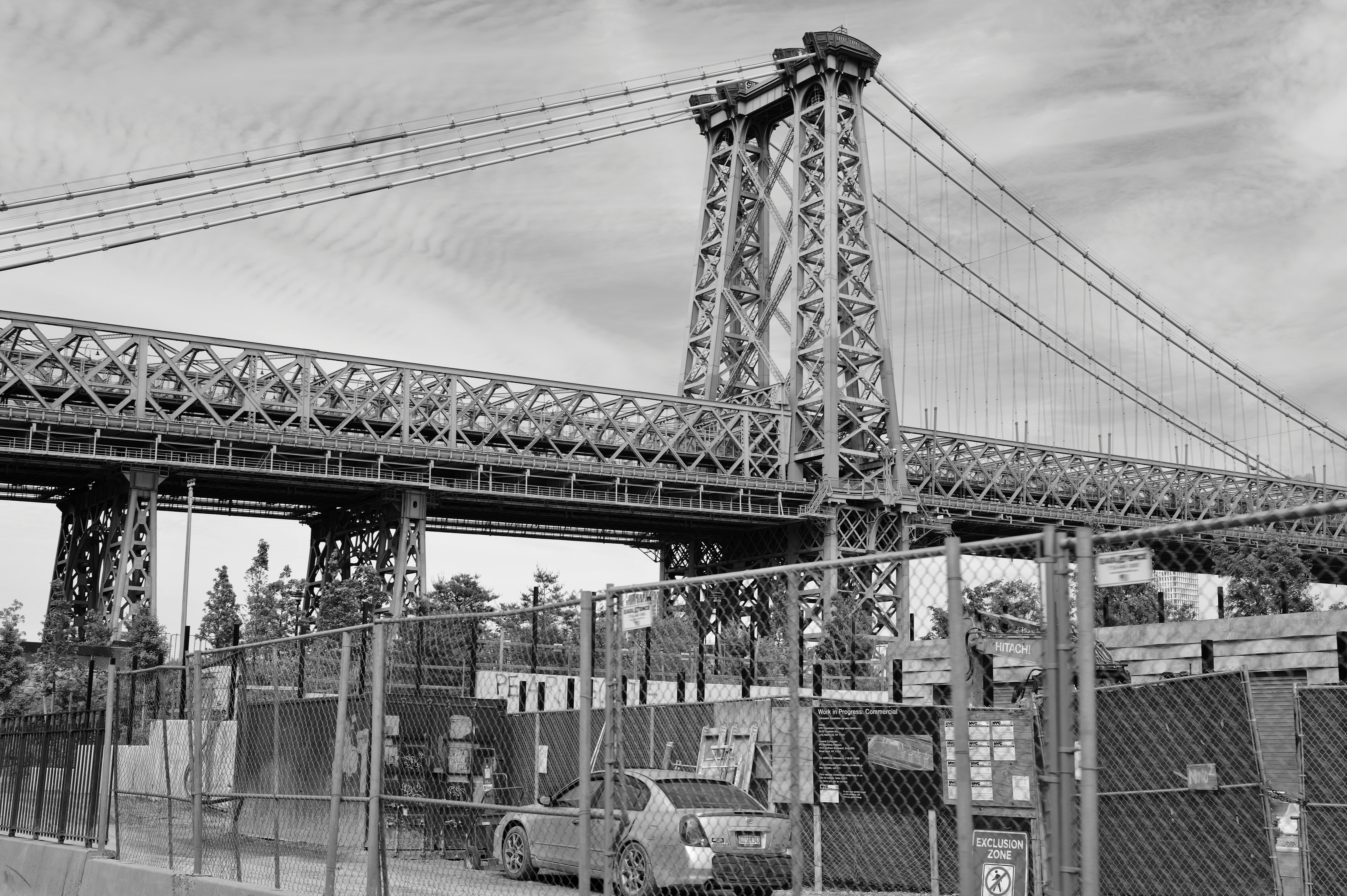 Grayscale Gantry: A Steel Bridge Over a Chain-Link Foreground