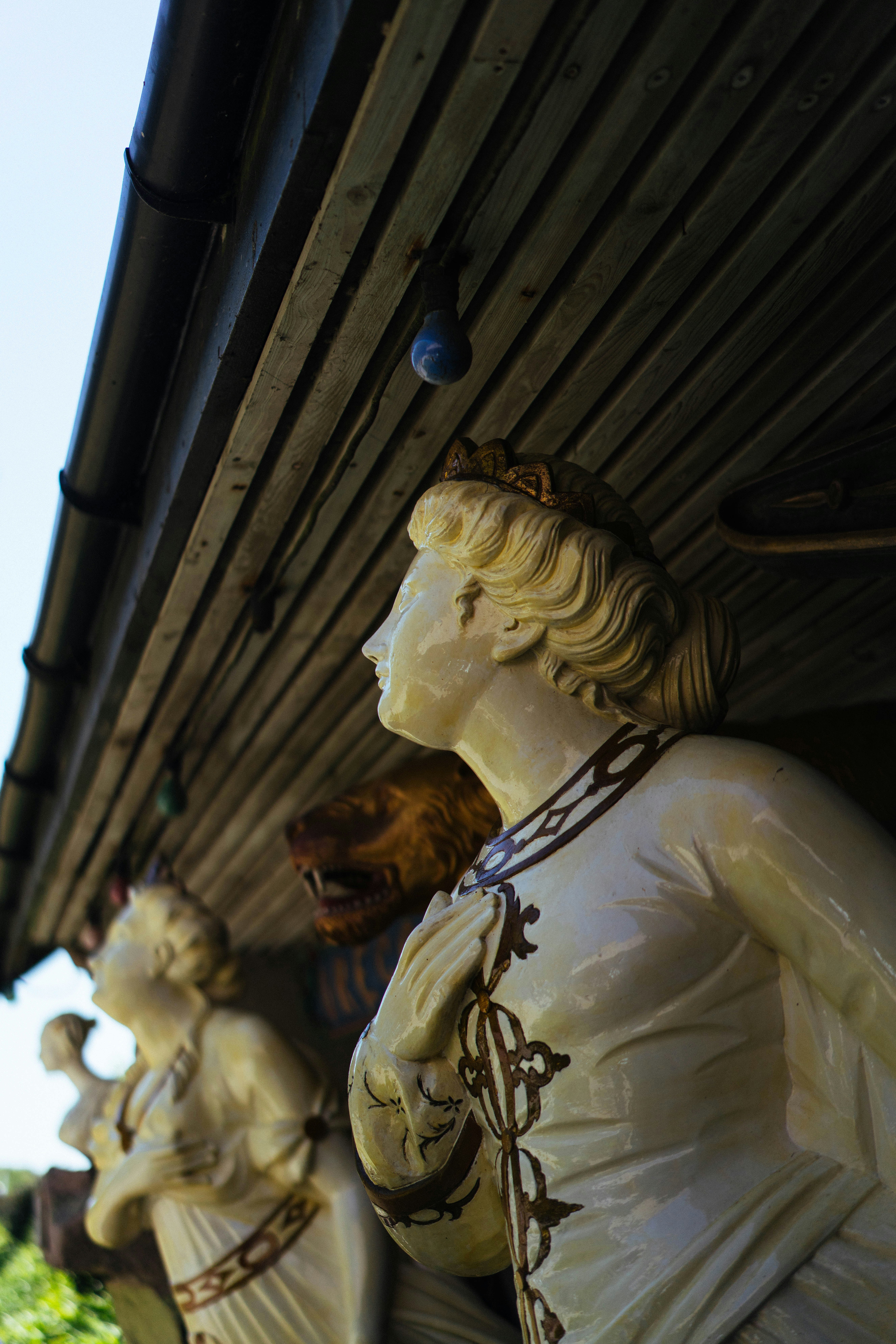 Statues Under a Wooden Overhang: A Row of Elegant Figurines in Soft Light