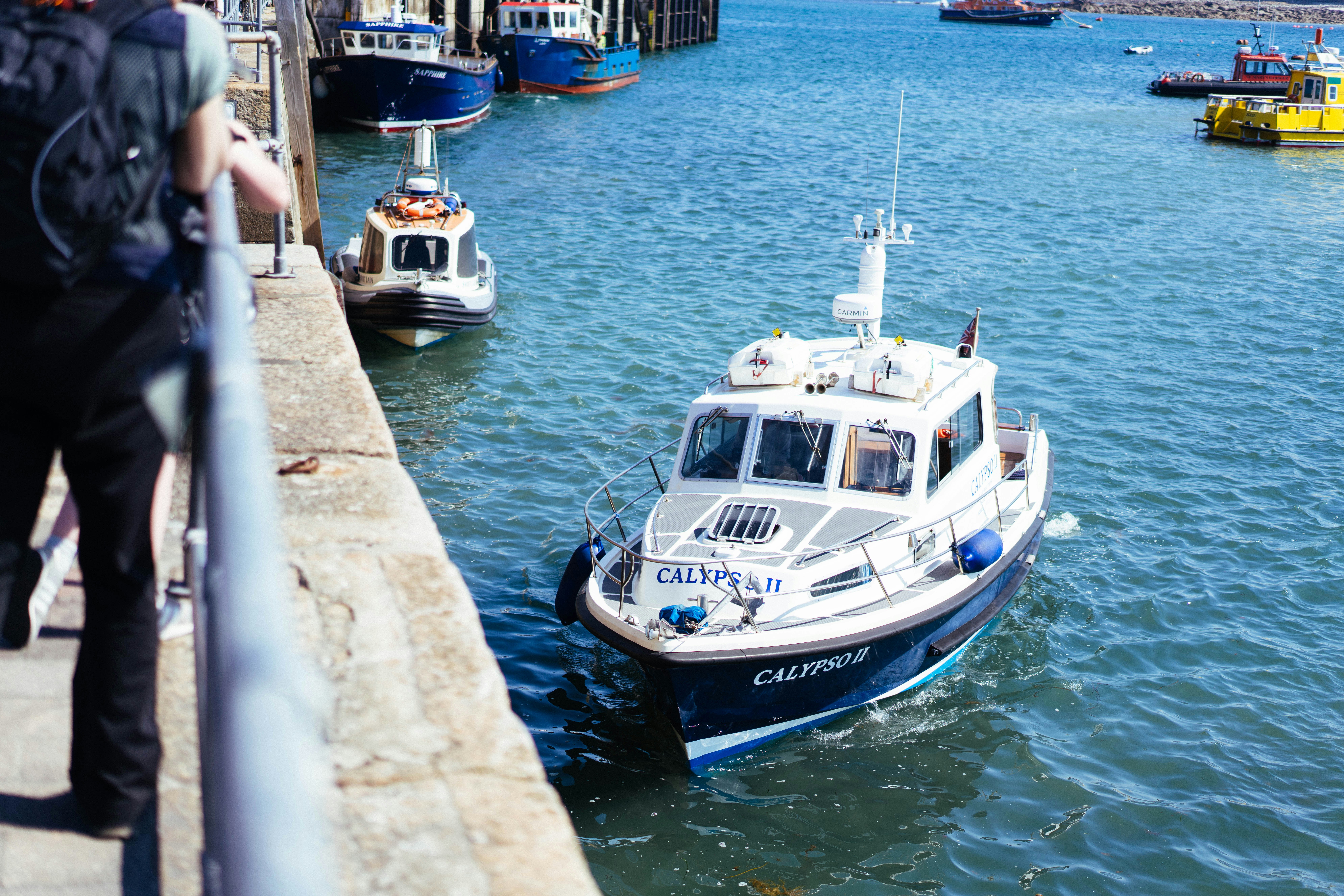 Boat steams toward the quay as a passerby gazes over the railing