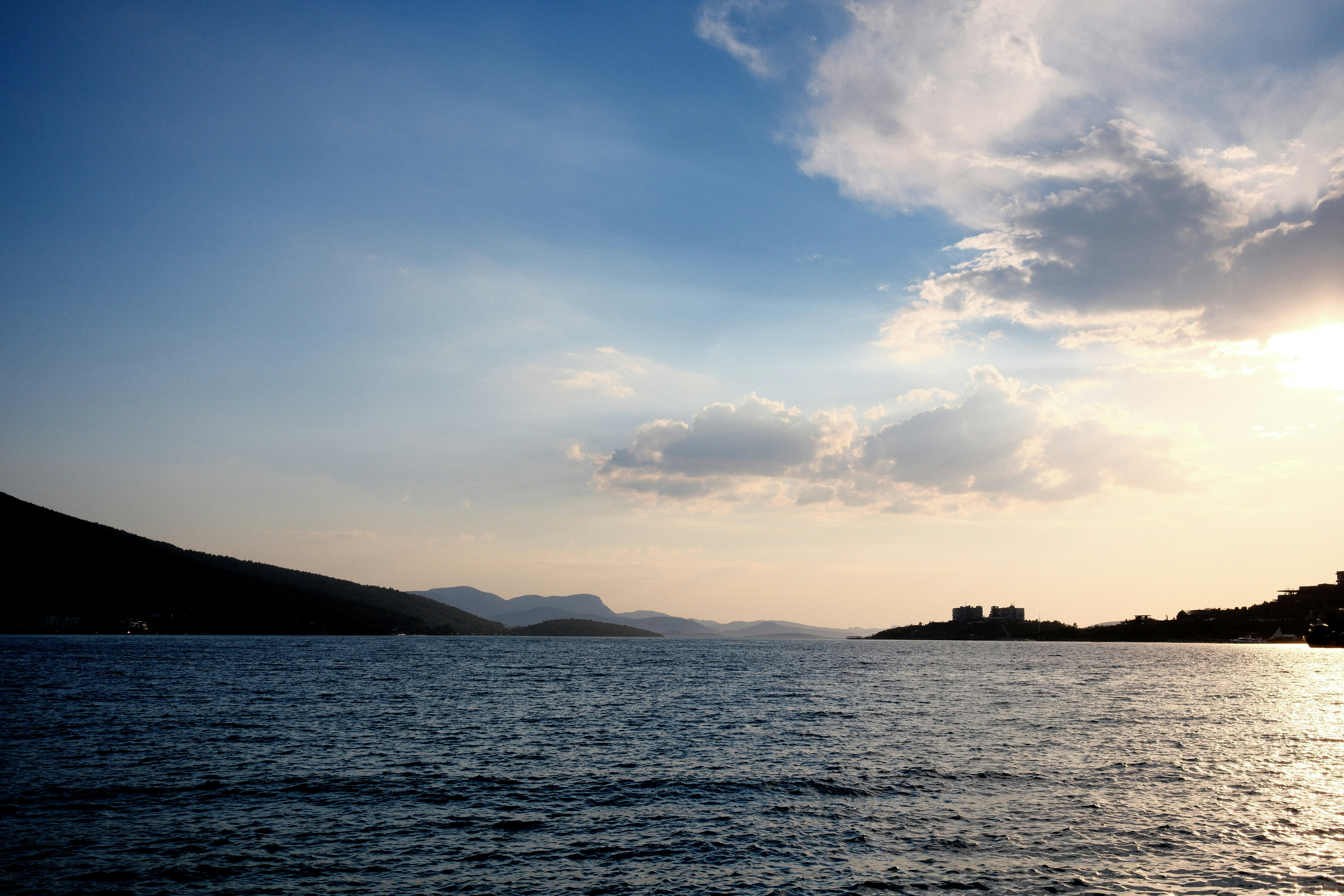 A calm sea with distant mountains under a sunset sky. photo – Free ...