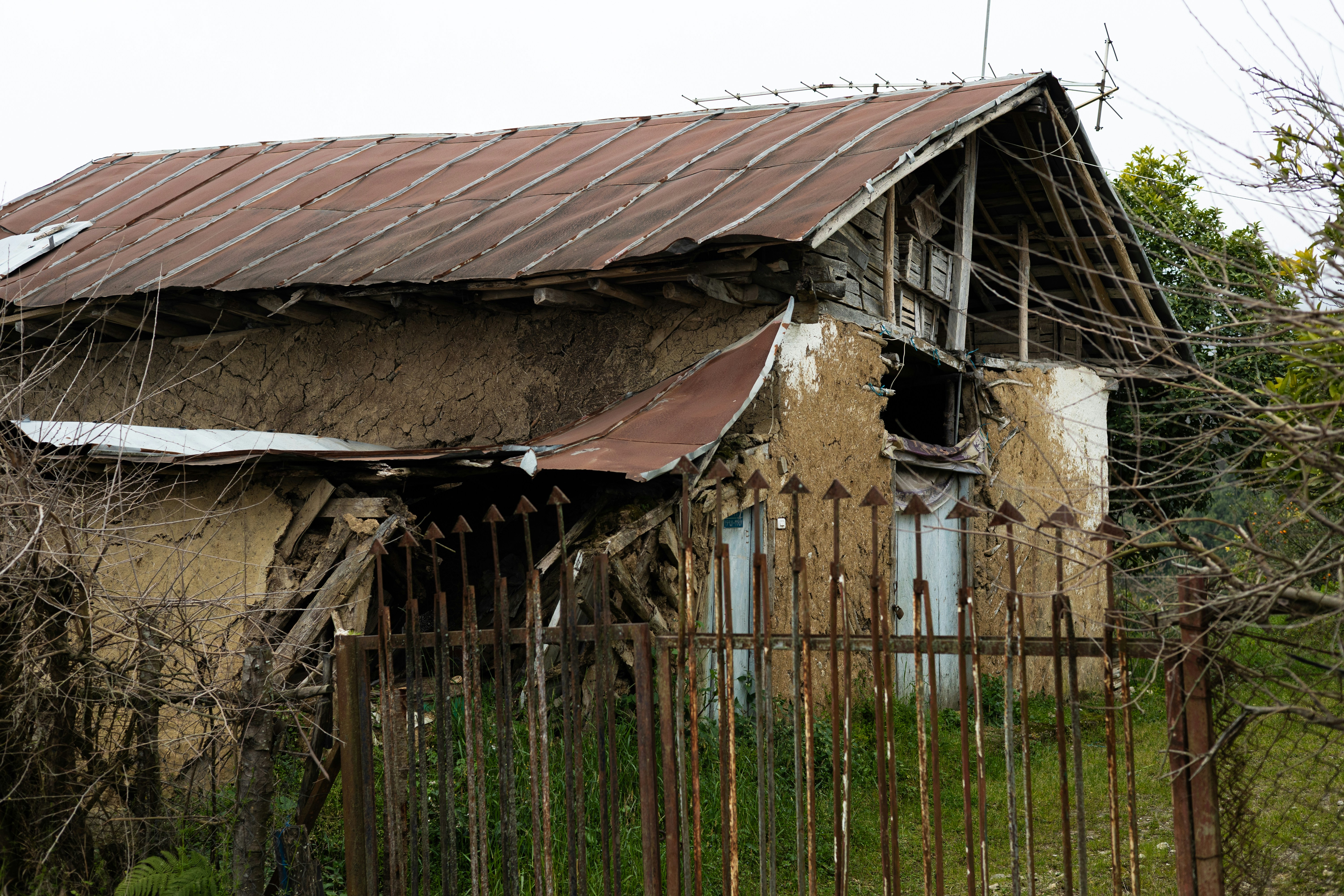 Weathered Roof, Weeping Walls: a Ran-down Cottage Bound by Rusted Rails