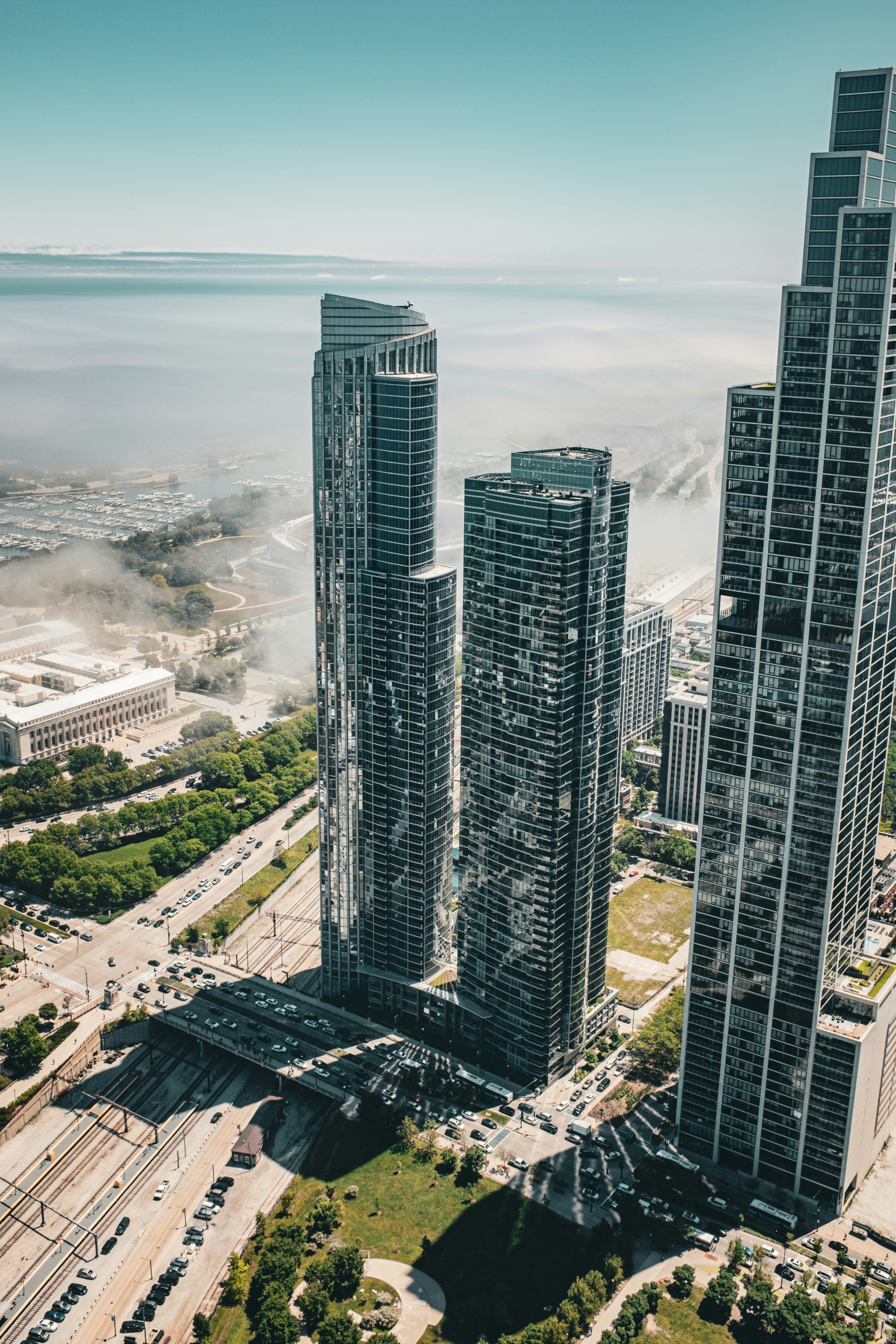 Aerial view of modern city skyscrapers, roads, and hazy sky.