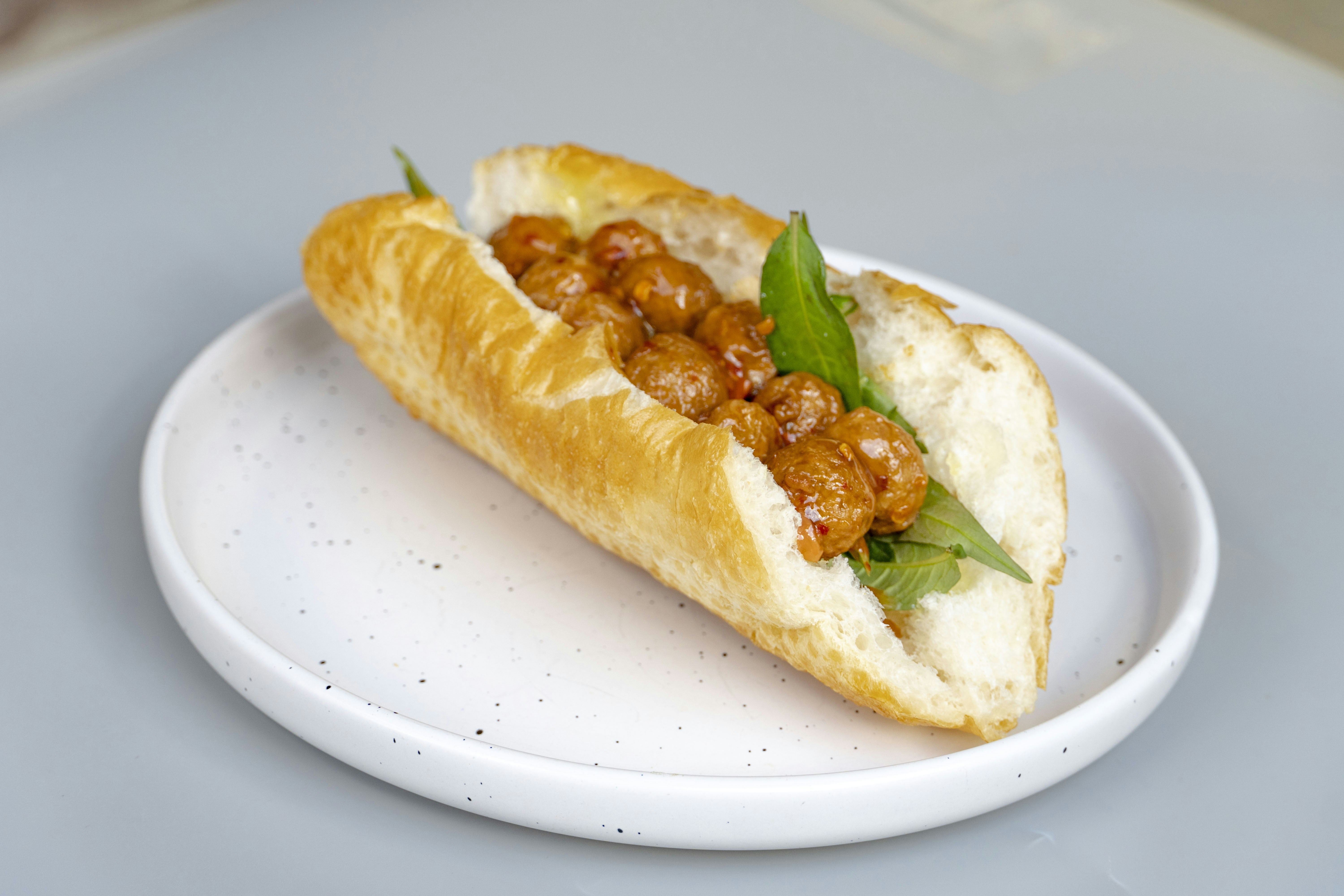 Crispy-bunned street hot dog with caramelized beans and greens