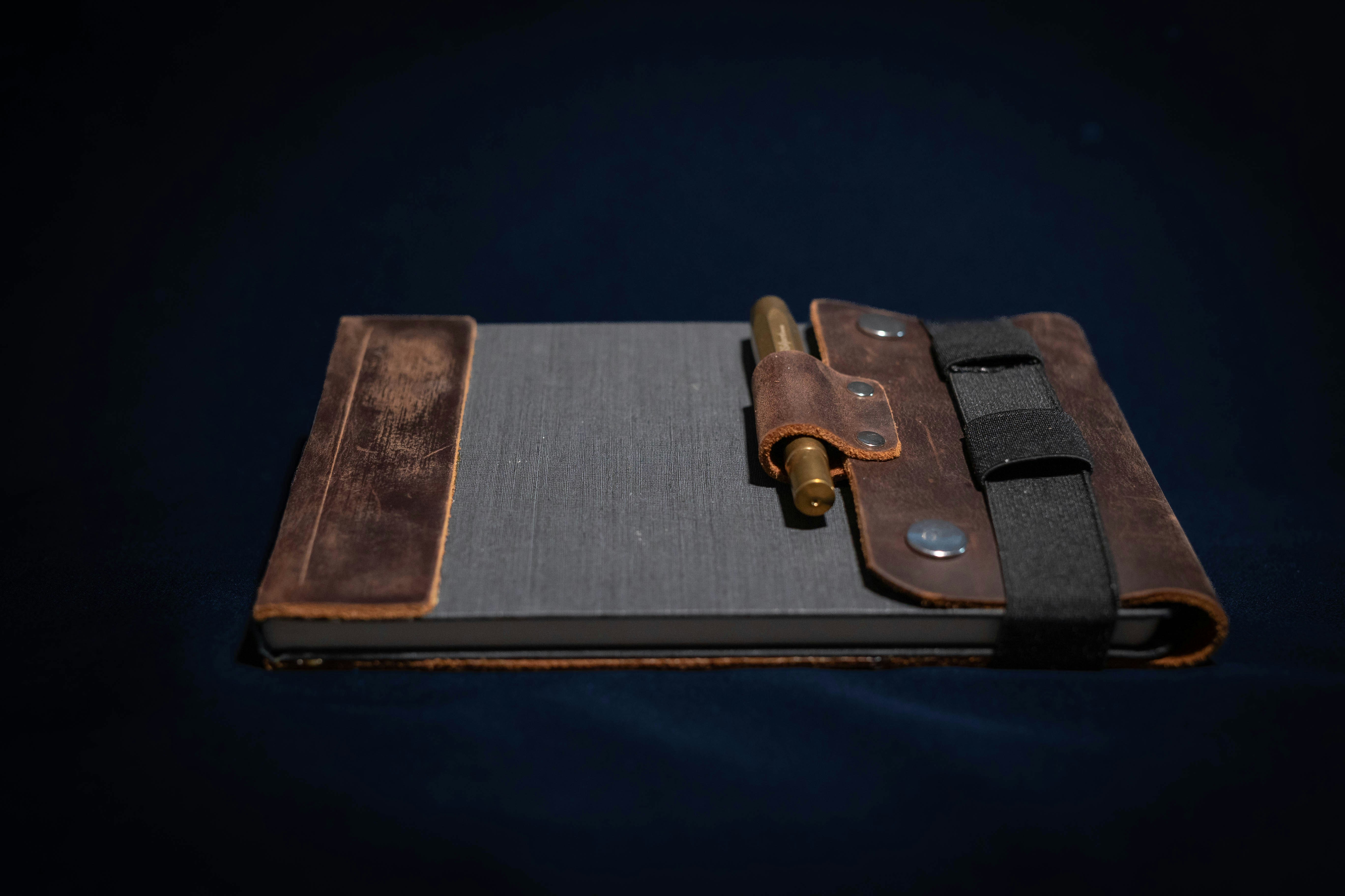 Leather-bound Notebook with Brass Closure Resting on Velvet Night