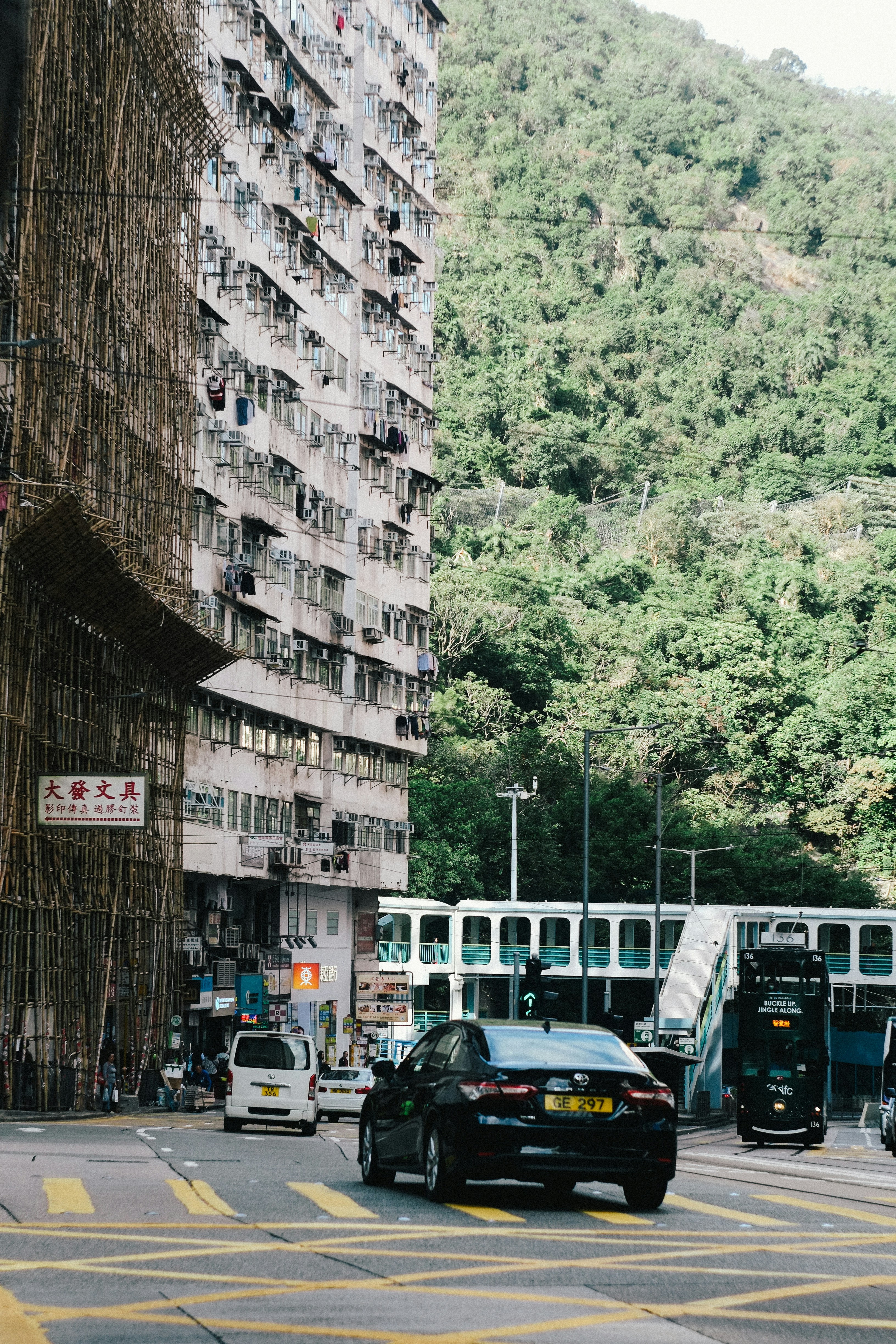 City street with old buildings, cars, and a green mountain.