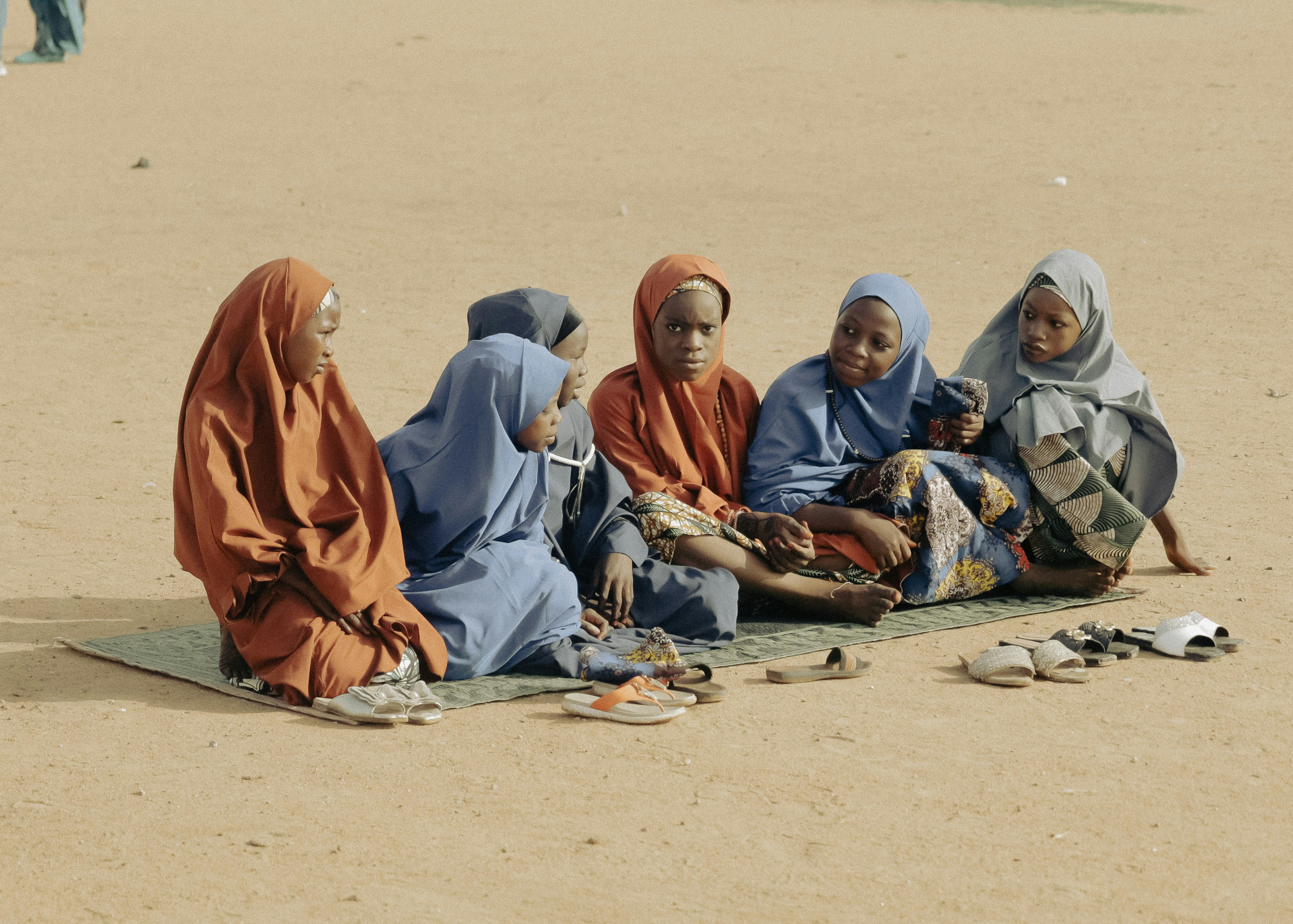 Solemn Gatherer: A Row of Shrouded Women in Earth-Toned Attire