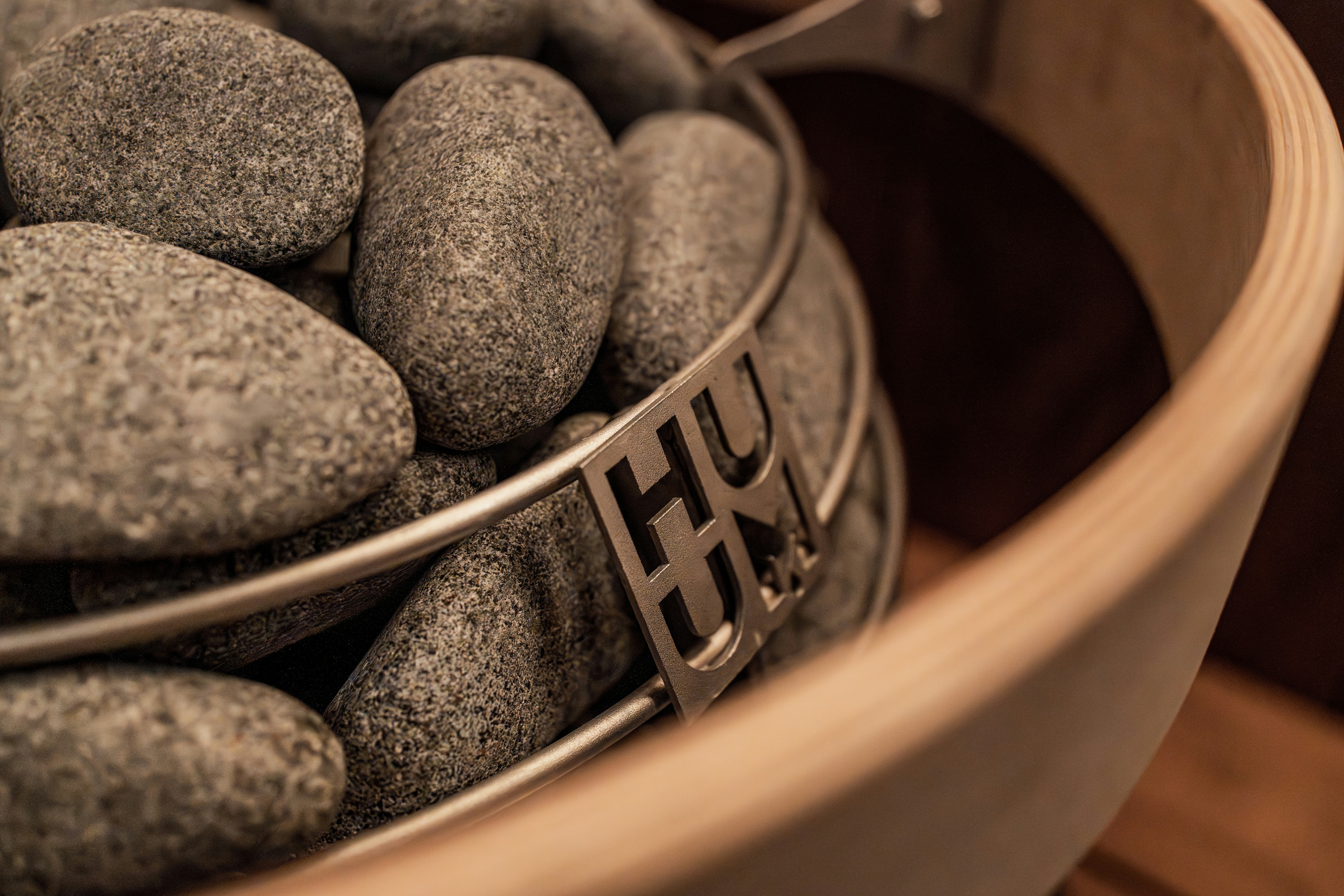 Sauna stones in a metal basket with wooden trim.