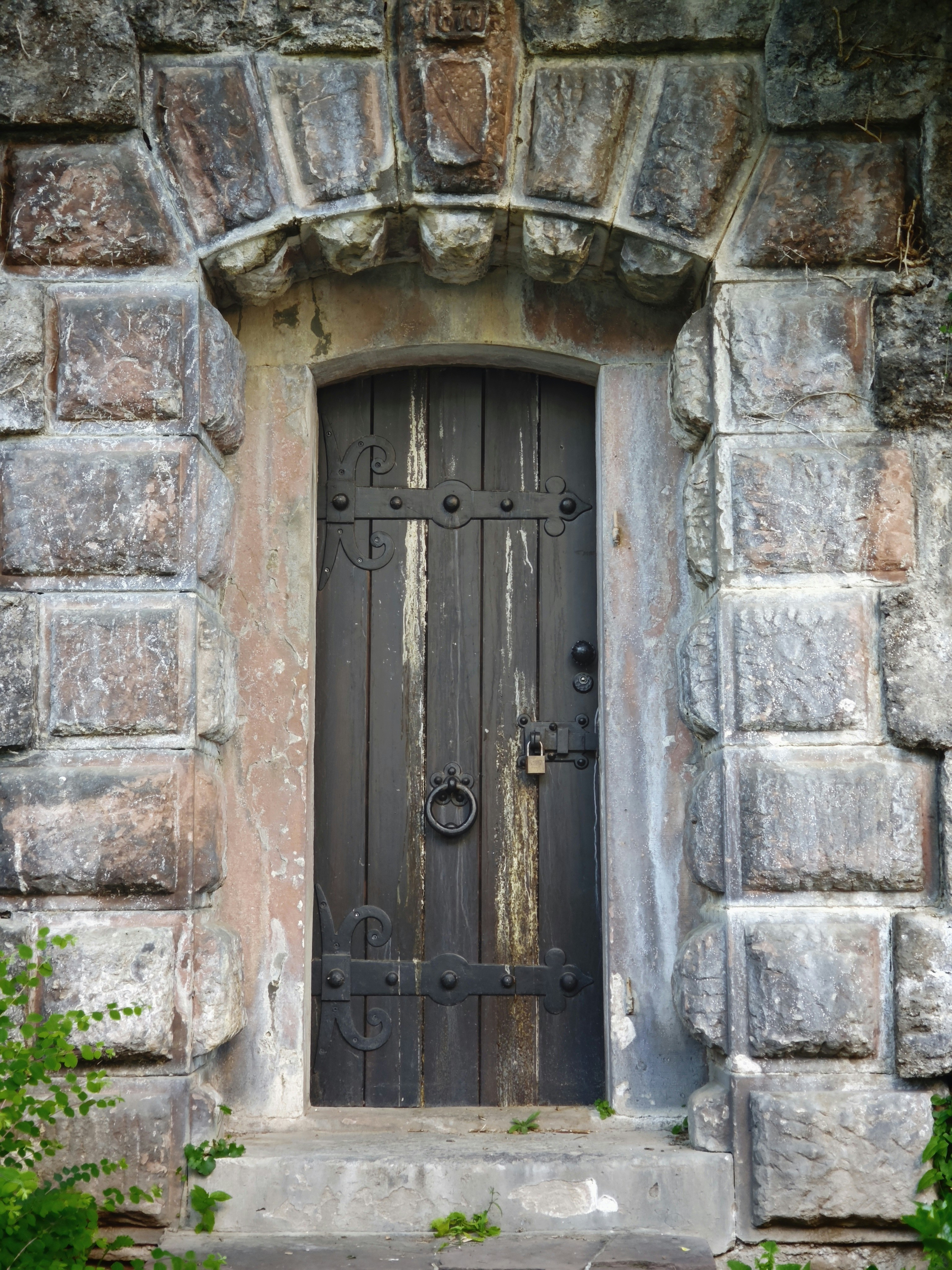 Weathered Portal: A Shrouded Door Within an Ancient Stone Arch