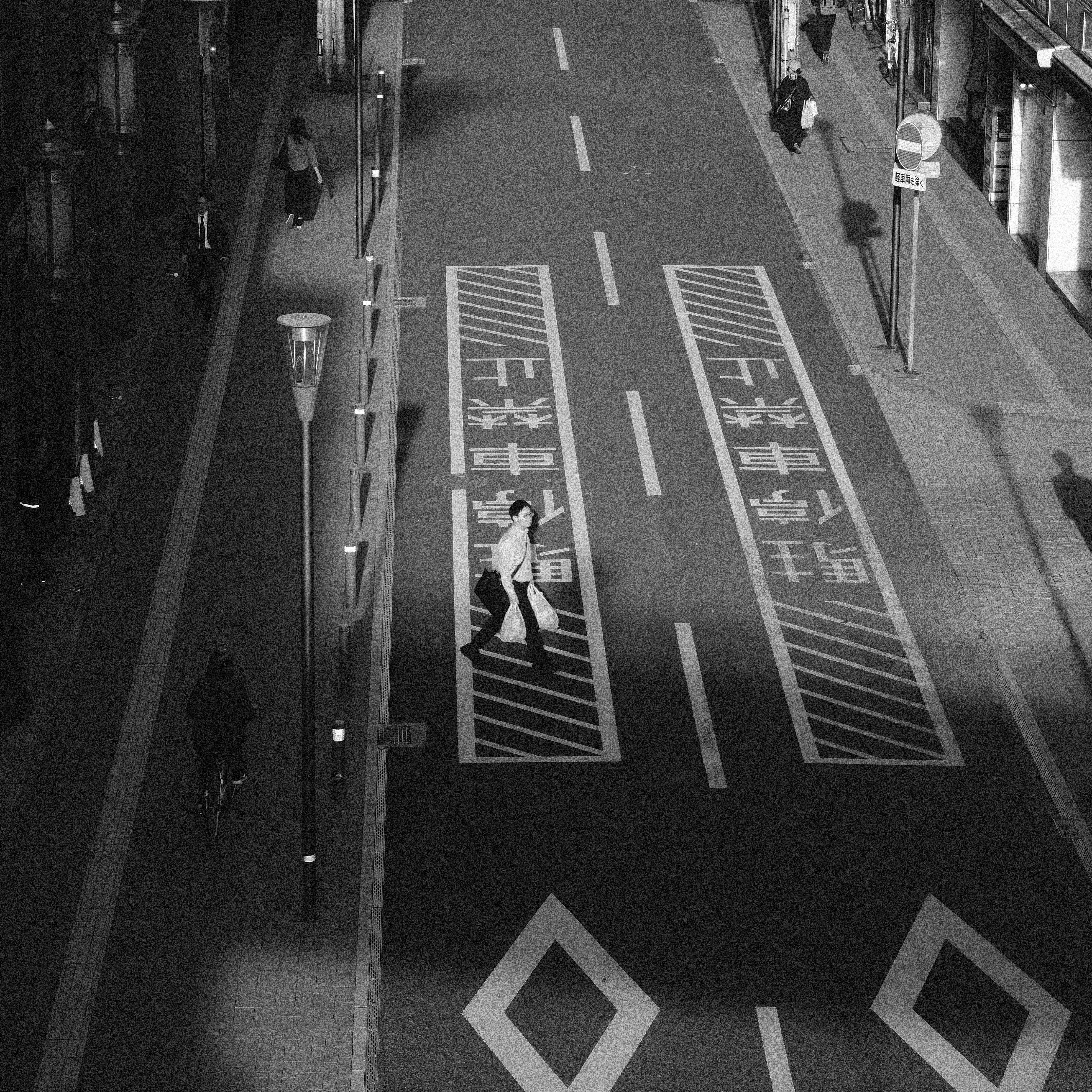 Midday Crossing: A Pedestrian Steps Between Striped Lanes on an Urban Street