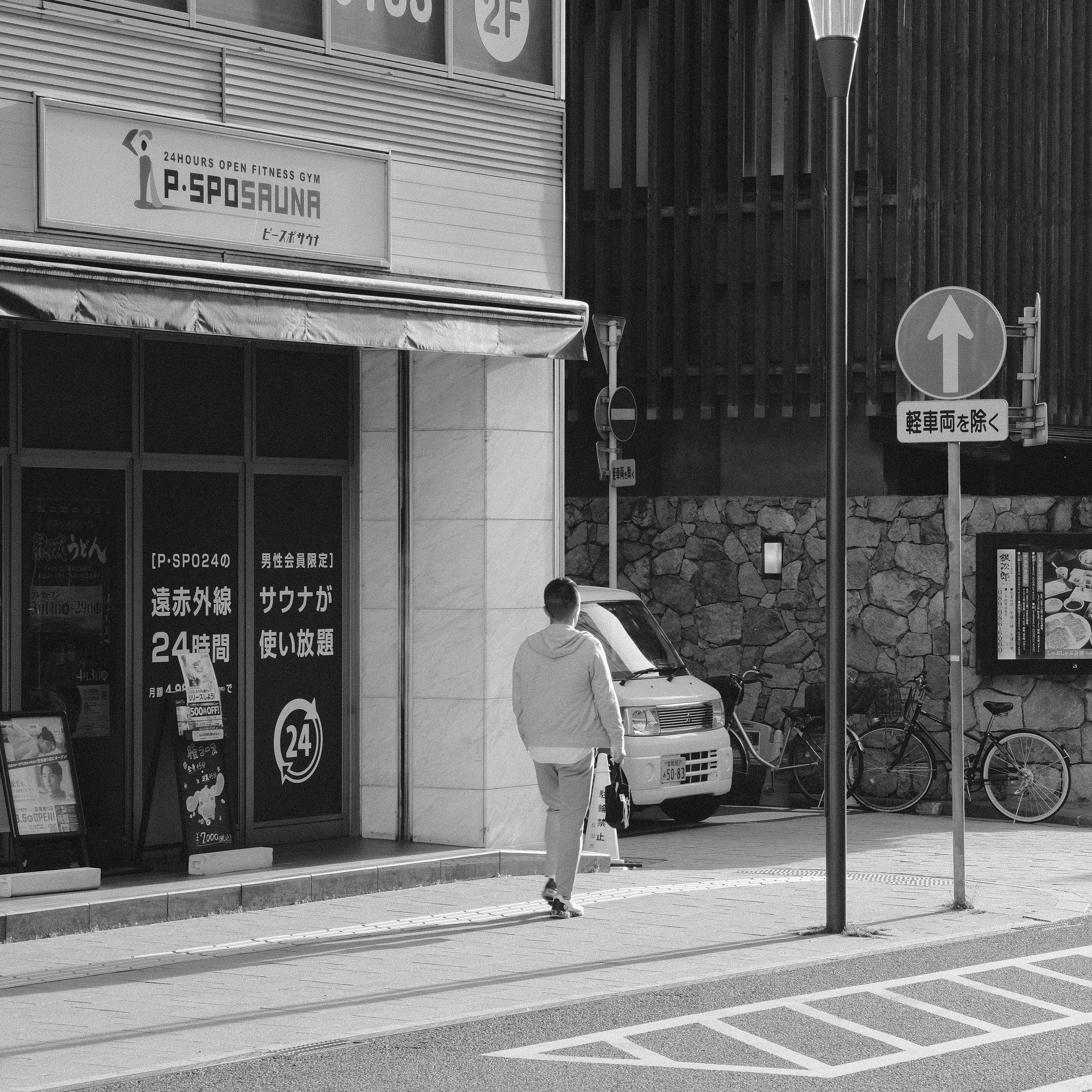Man Walking Past a Quiet Urban Shopfront in Monochrome