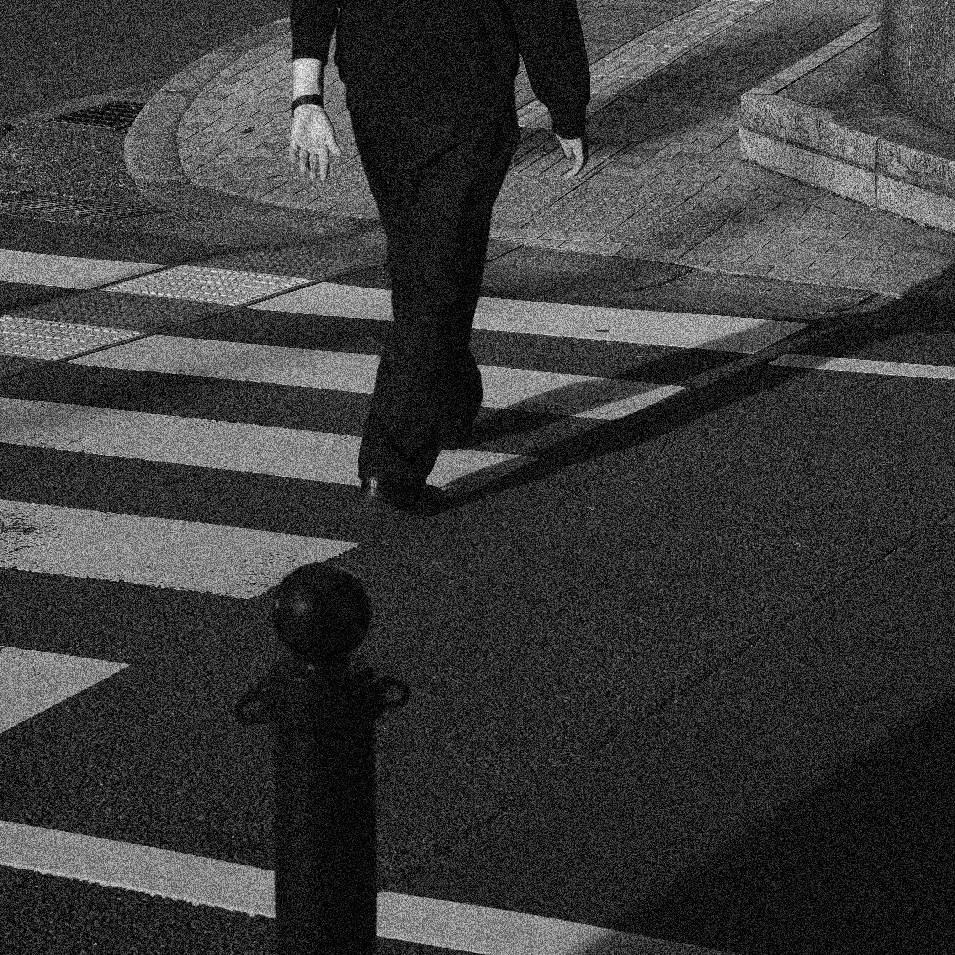 Shadowed Crossing: The Quiet Walk of a Figure Across a Sunlit Stripe