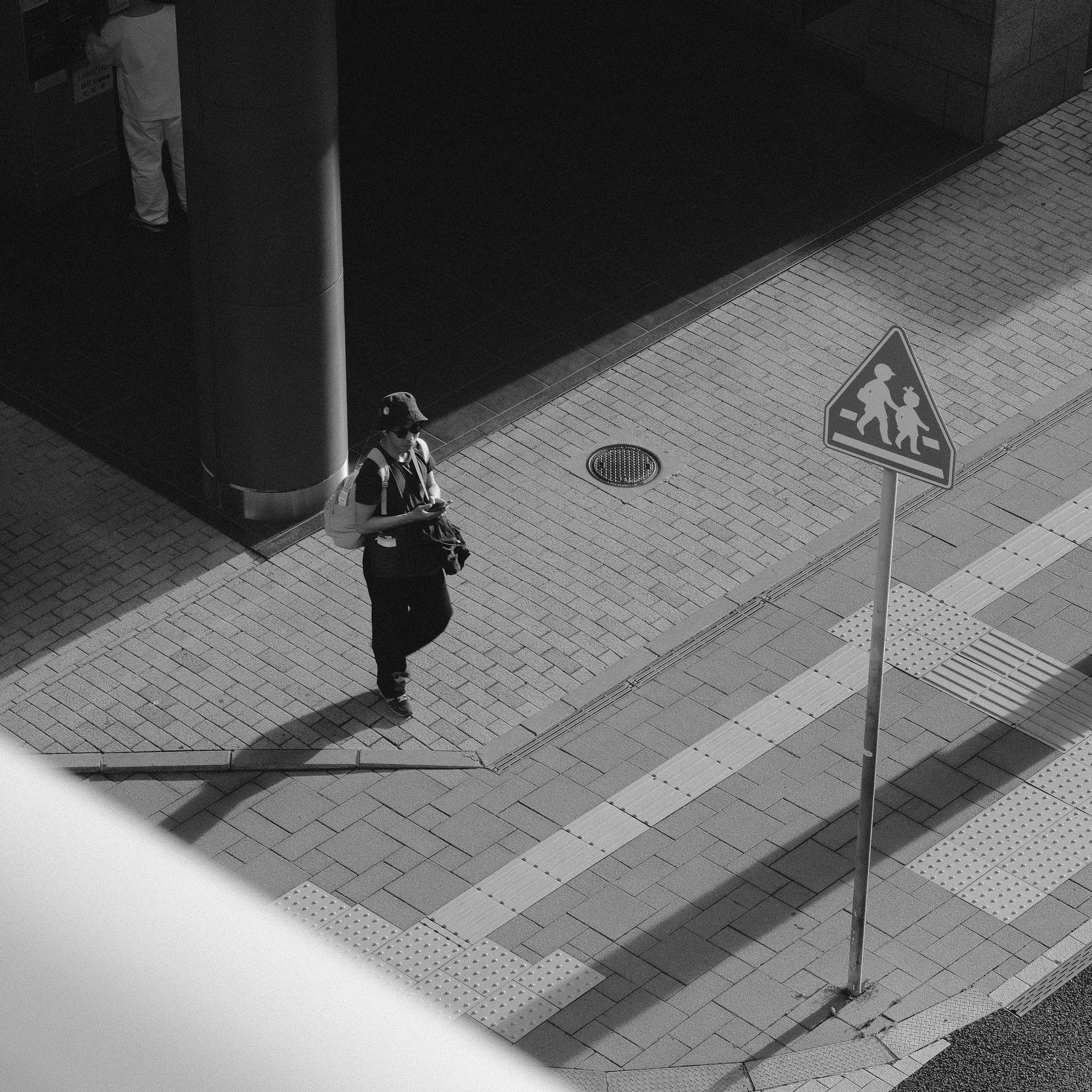 Midtown Stroll: A Photographer's Moment Beneath a Pedestrian Sign