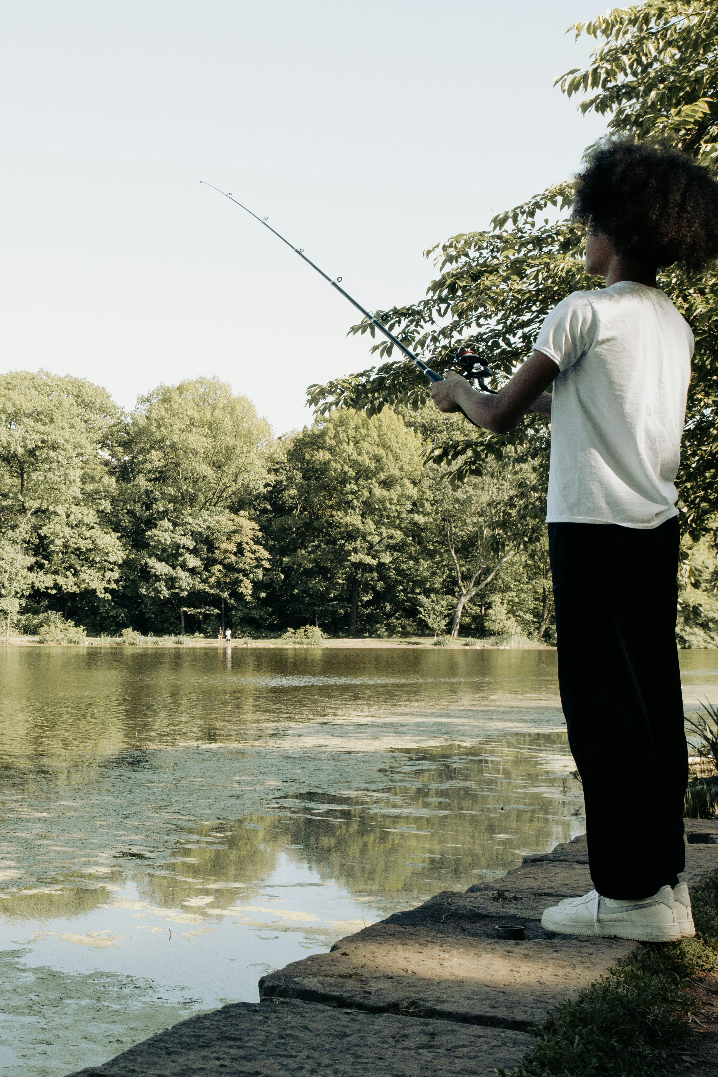Focused Silhouette: A Youth Casts a Quiet Line by Riverside