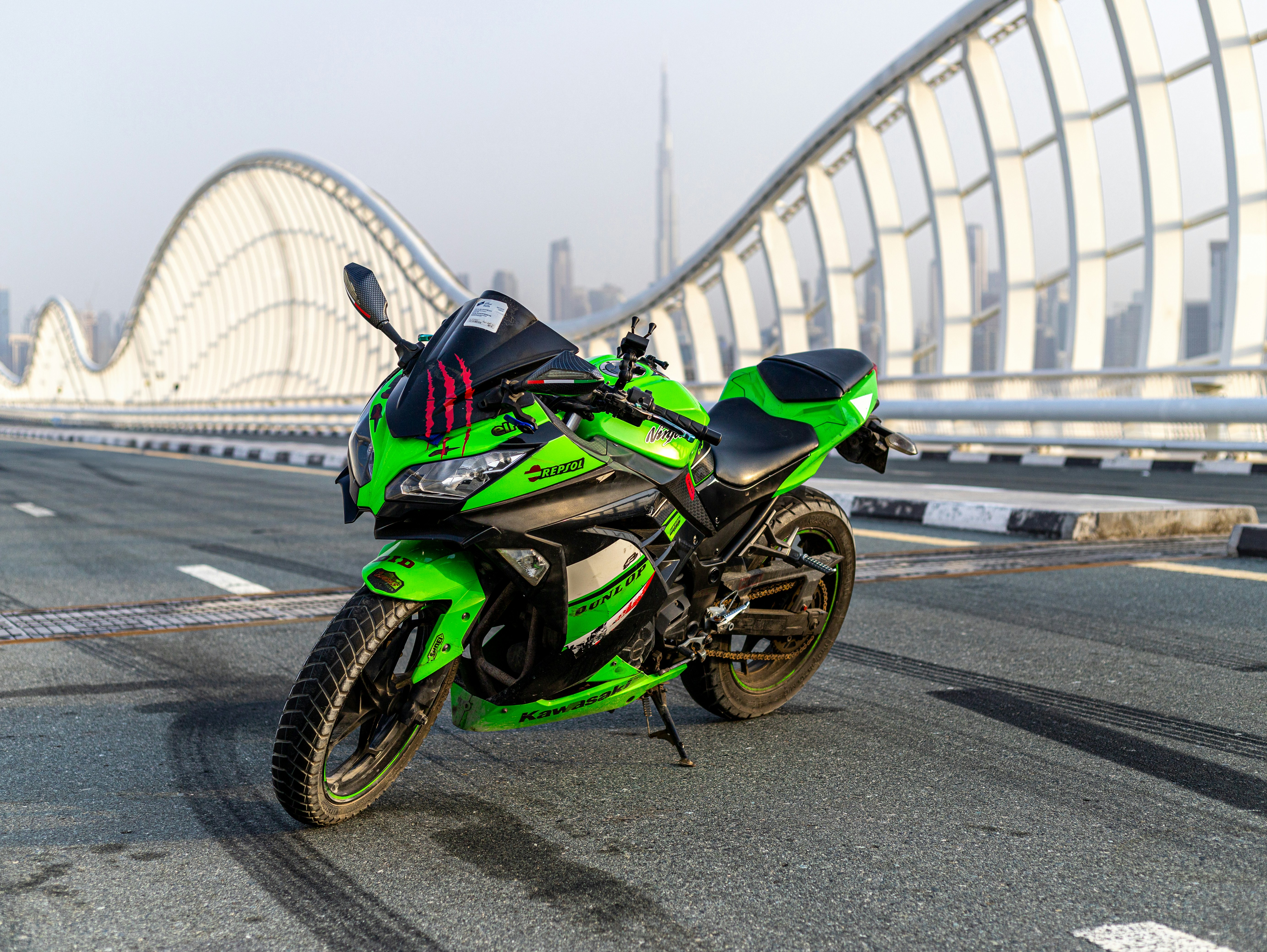 Neon-green Kawasaki rests on a sunlit bridge with sweeping arches