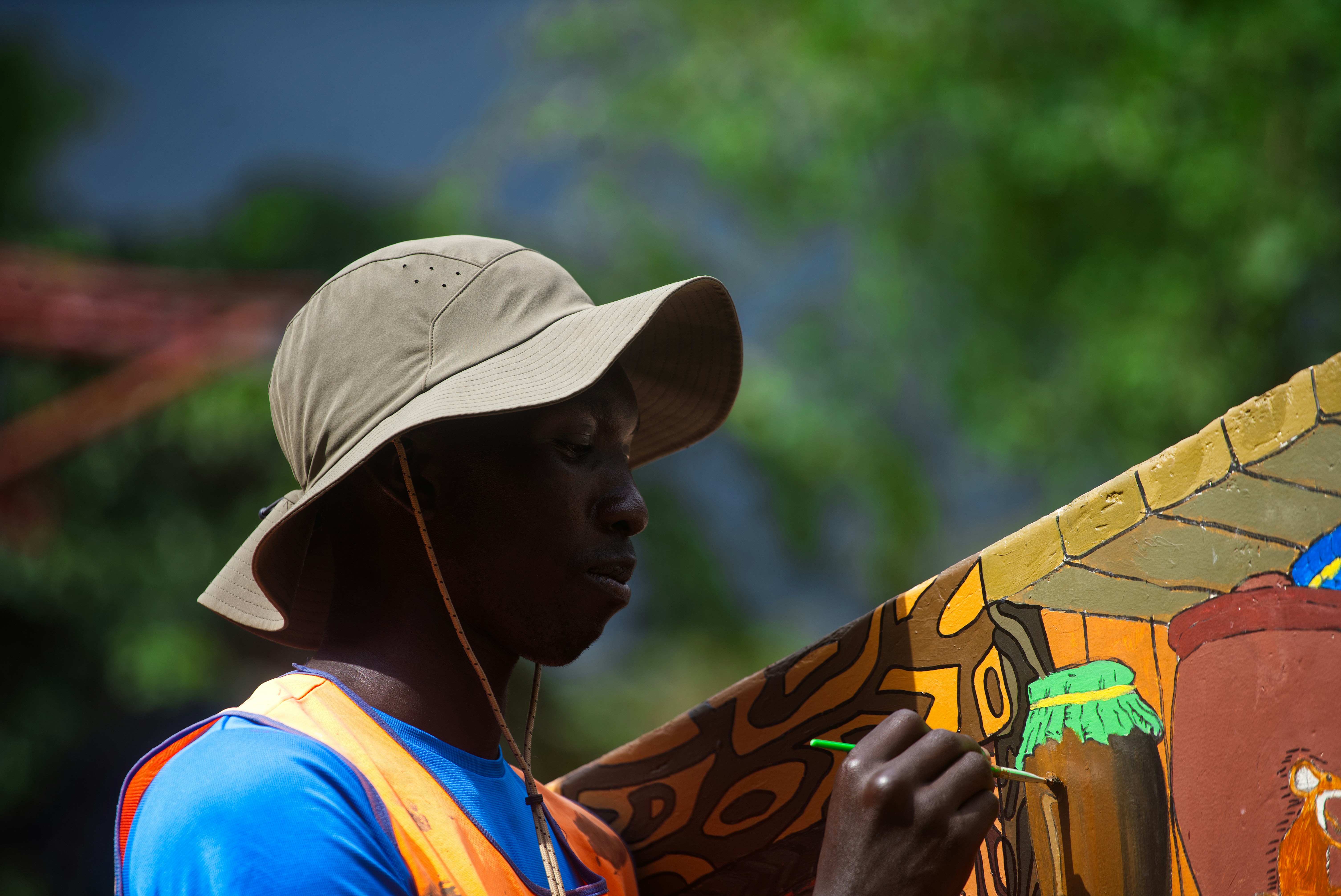 Portrait of a mural painter in a sunhat working on a vibrant panel