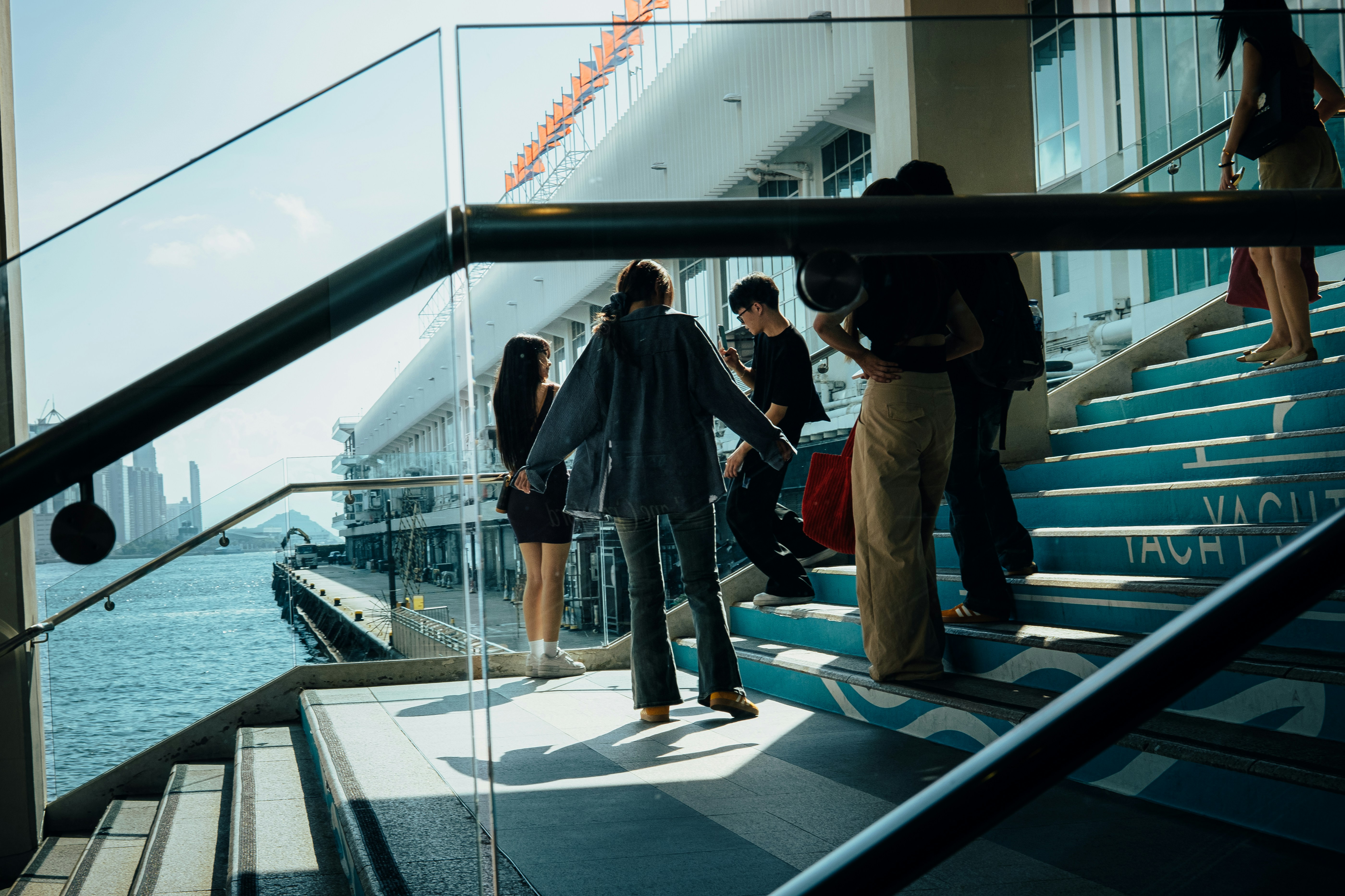 Steps of Connection: People Gather on a Glass-Front Terrace by the Sea