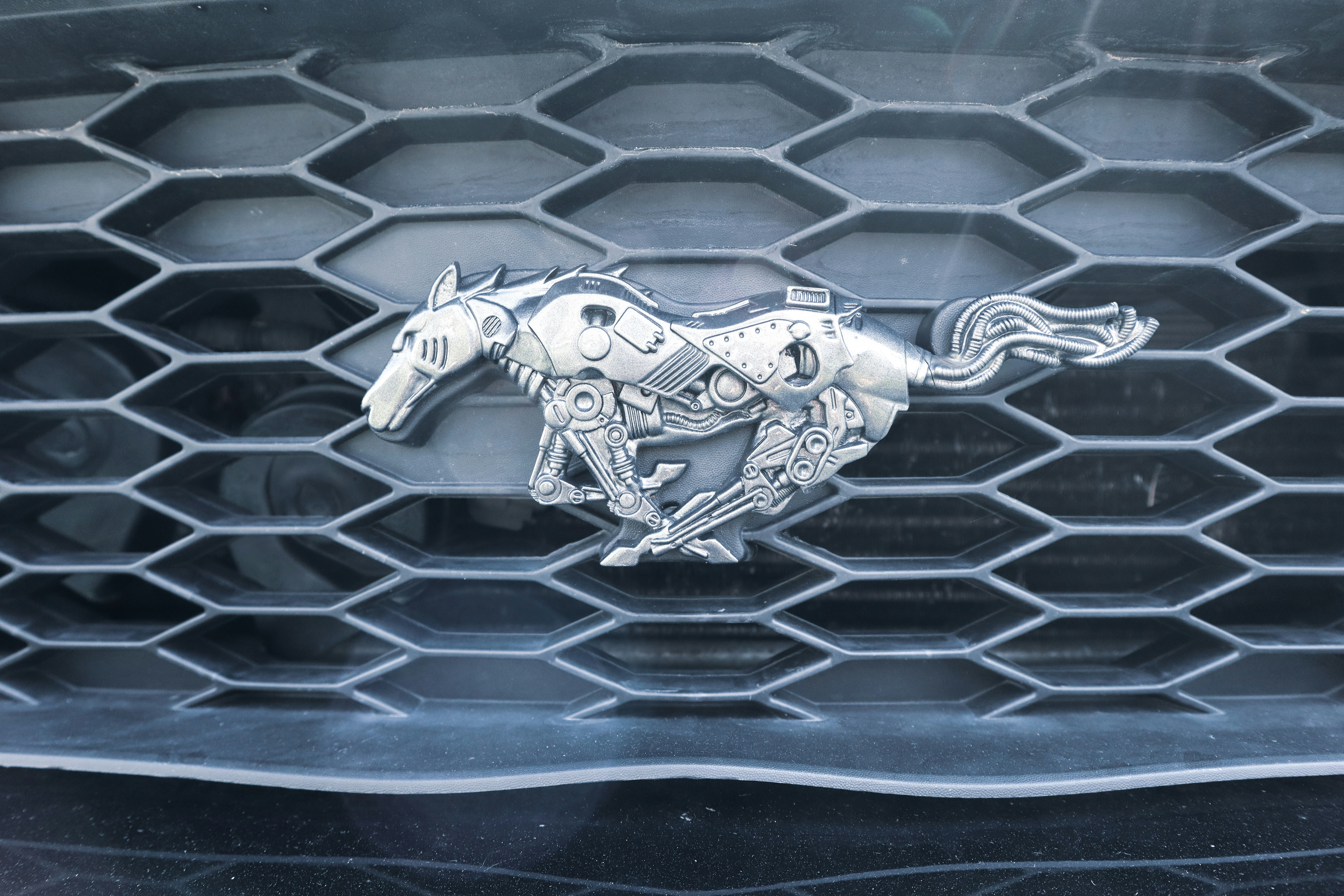 Mechanical Mustang on a Grille: A chrome emblem in motion