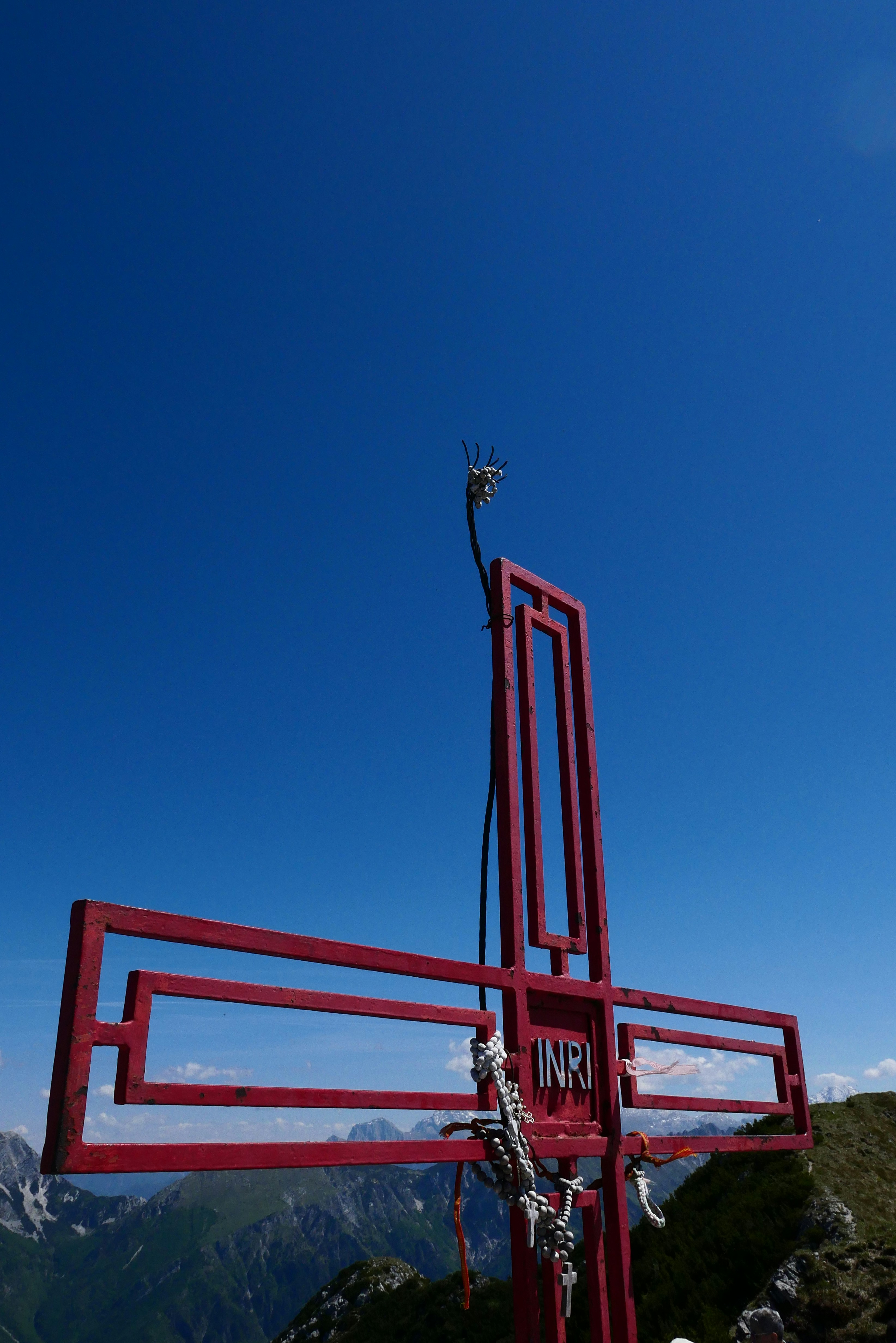 Red alpine cross atop the blue expanse