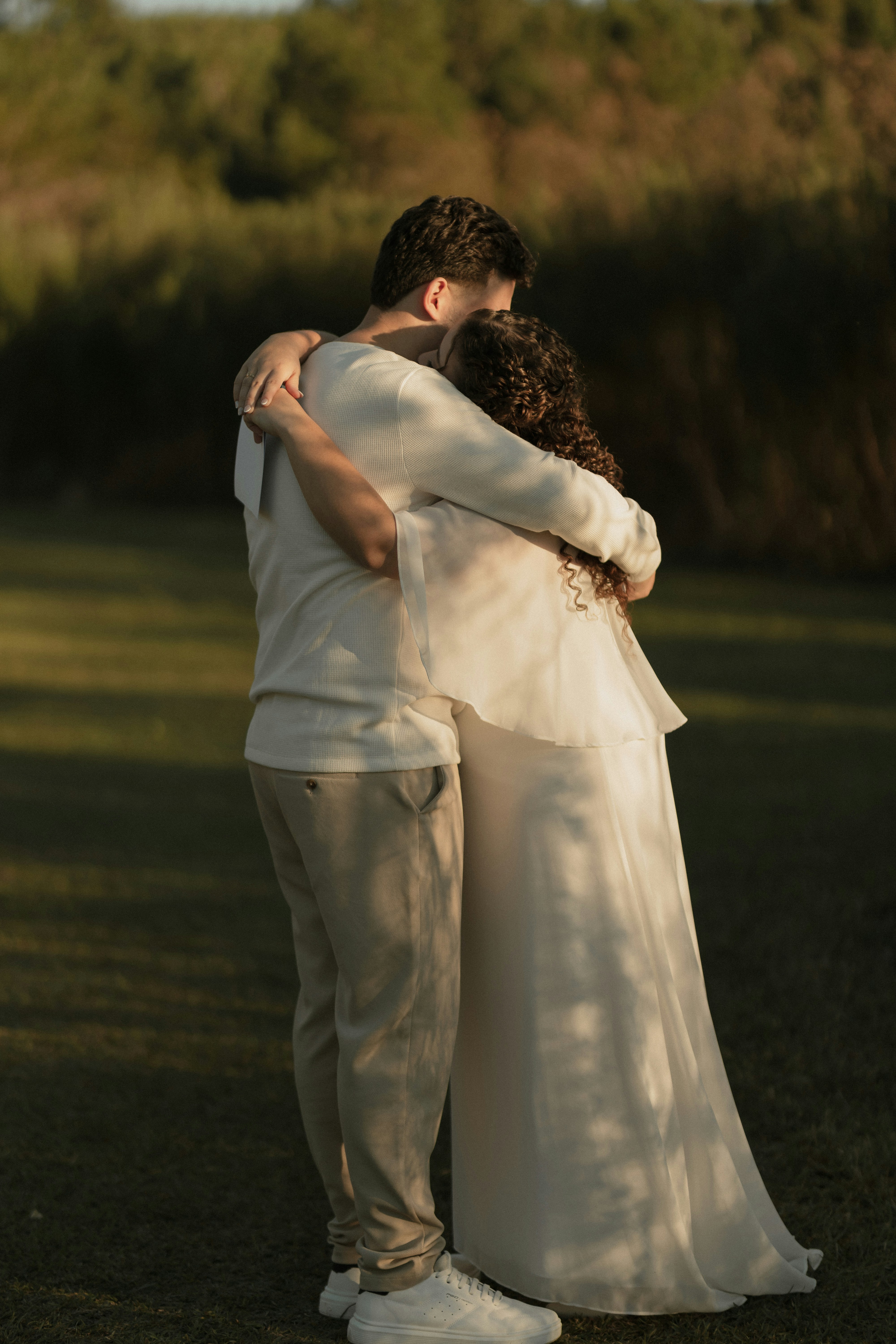 Couple embracing lovingly in a sunlit green field.