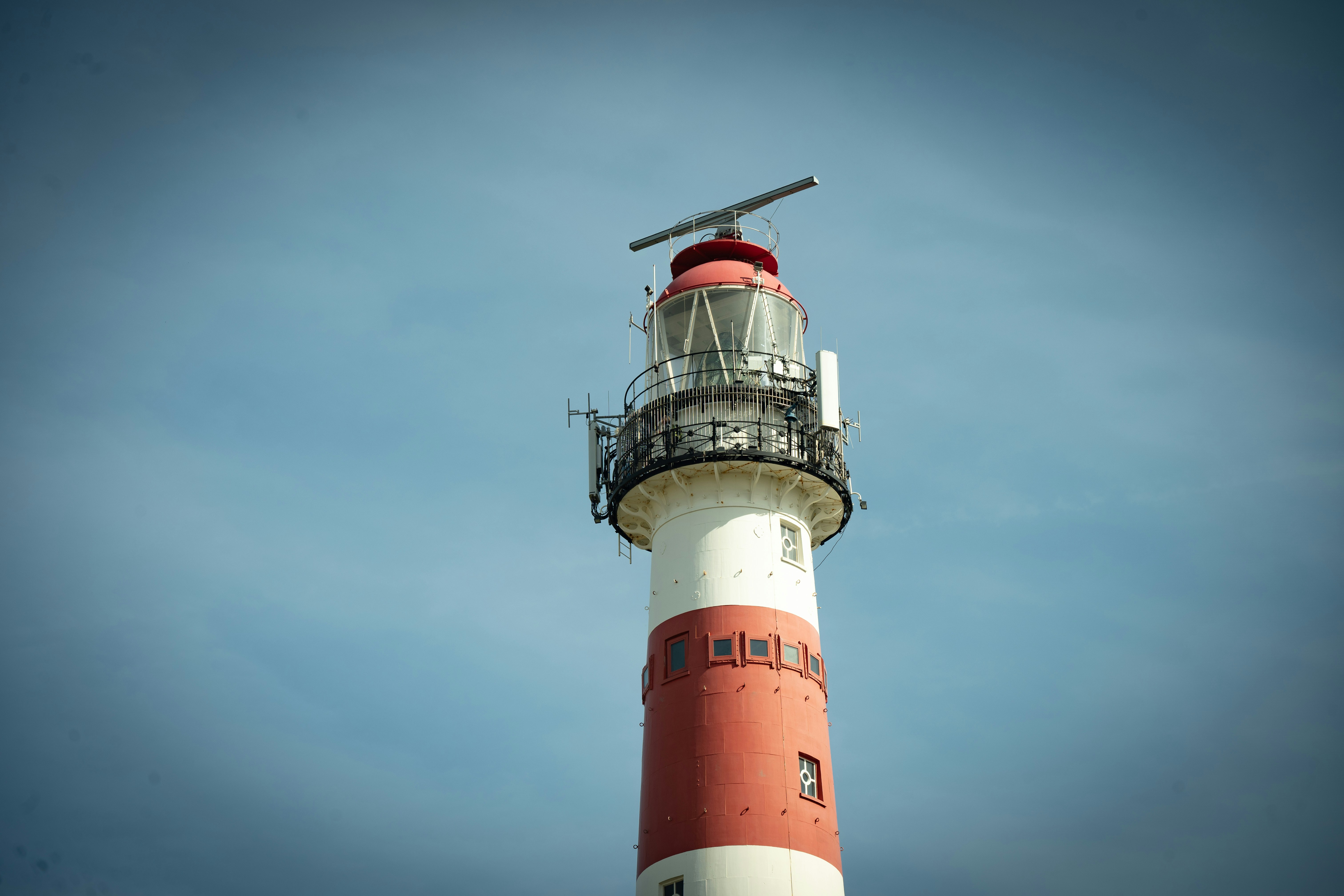 Beacon in the Blue: A Tall Red-White Tower Reaches for Clear Skies