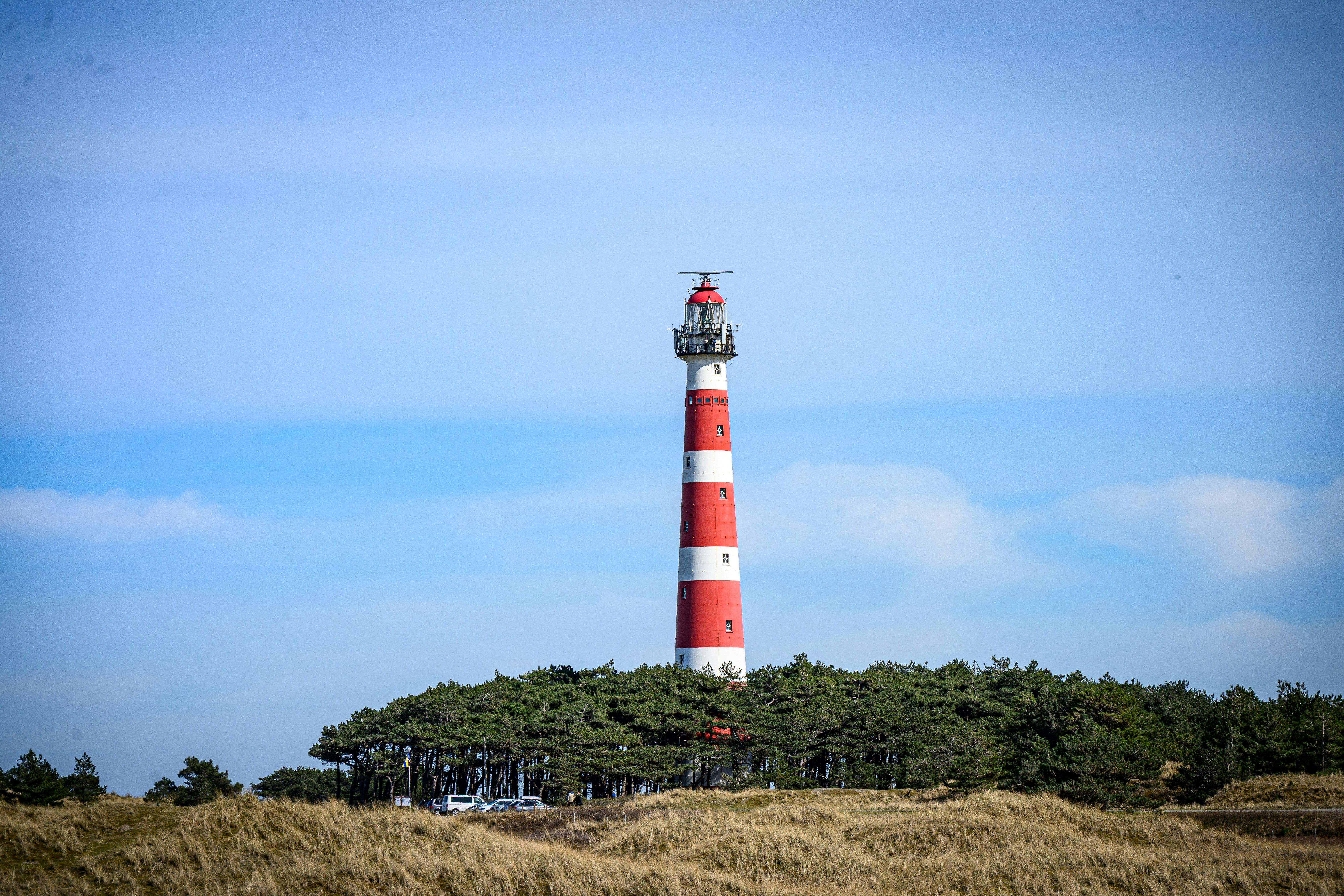 Lighthouse with red and white stripes on a green hill.