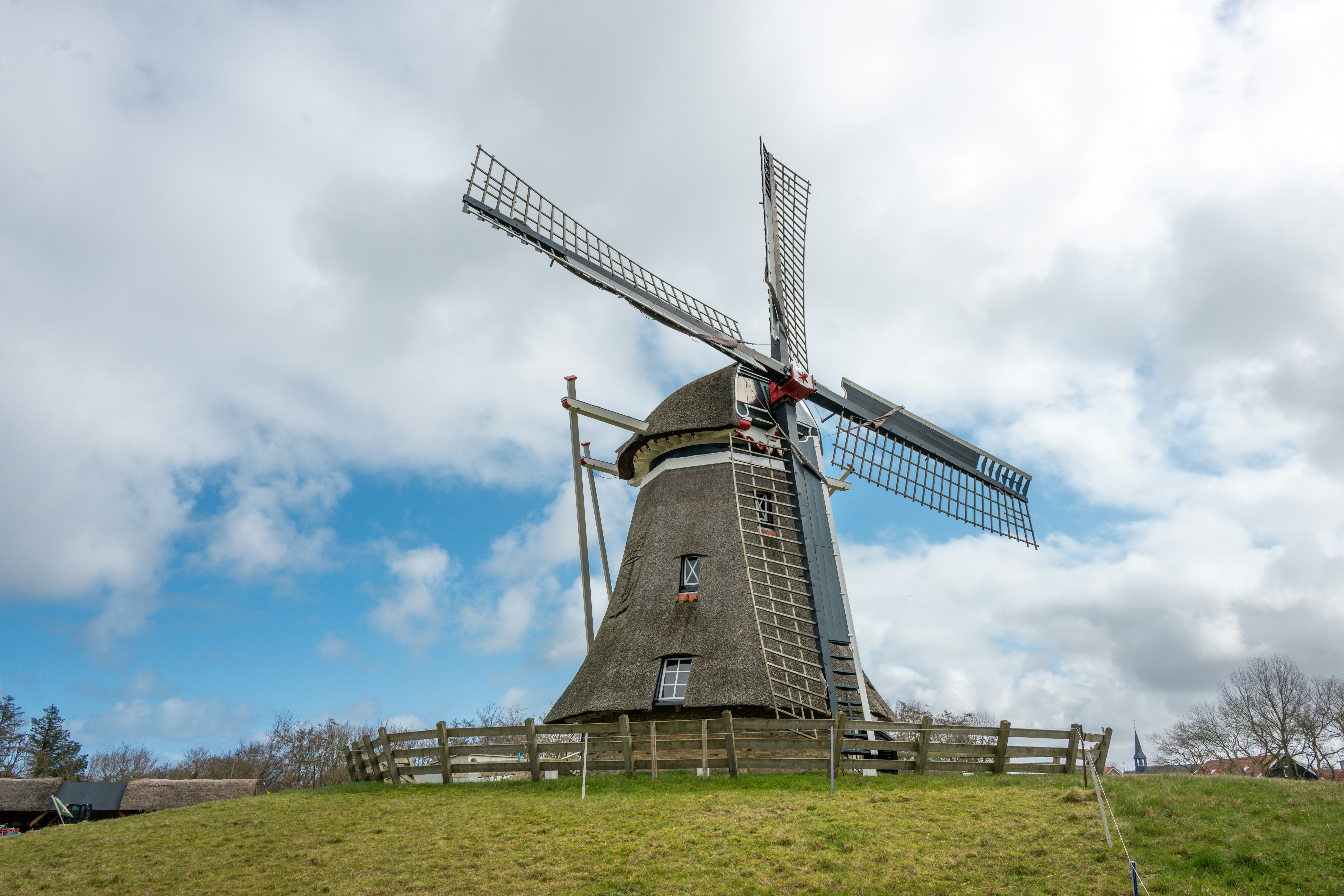 Traditional windmill on a grassy hill under a cloudy sky.