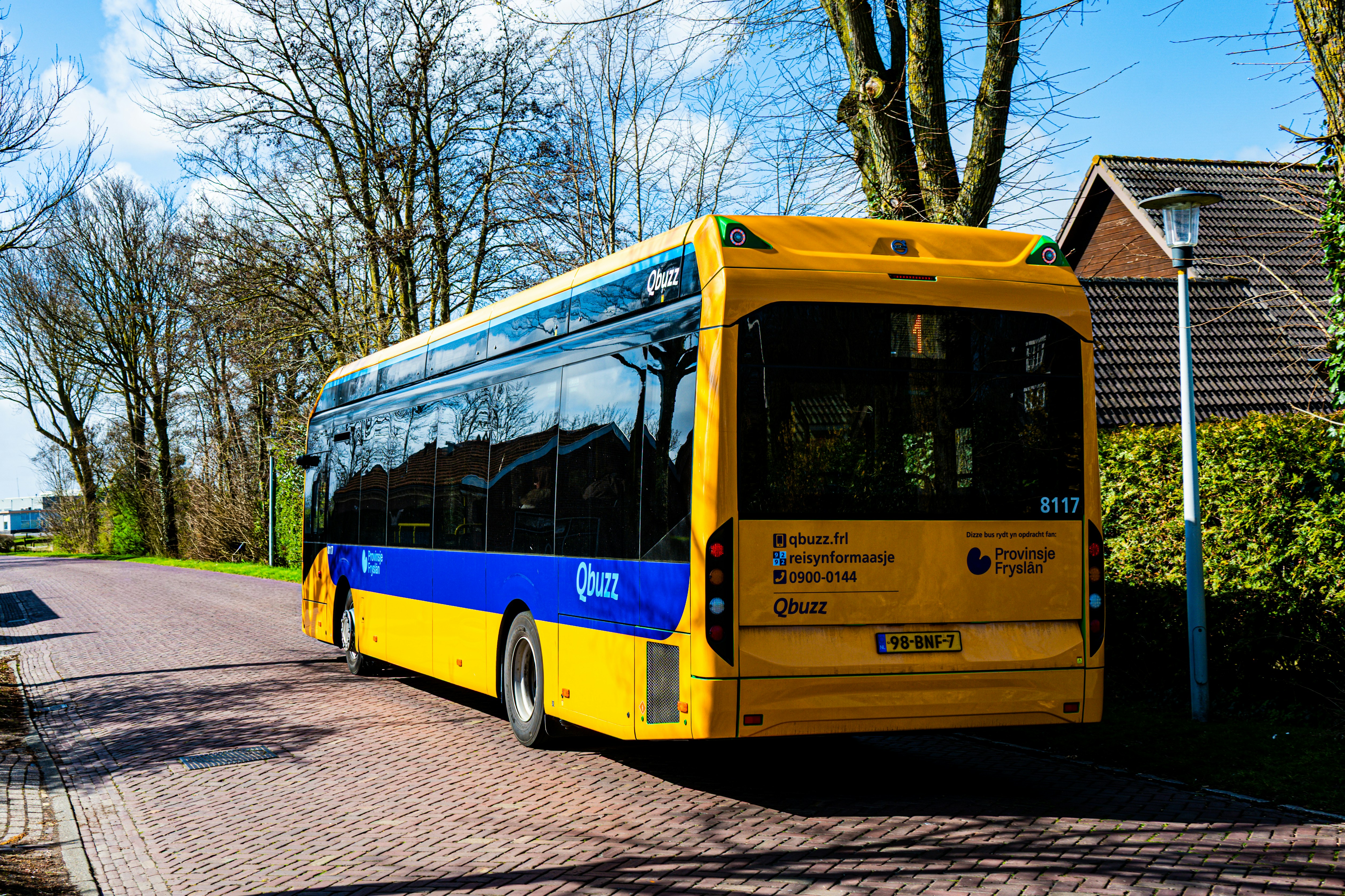 Yellow and blue city bus at curb in a residential street