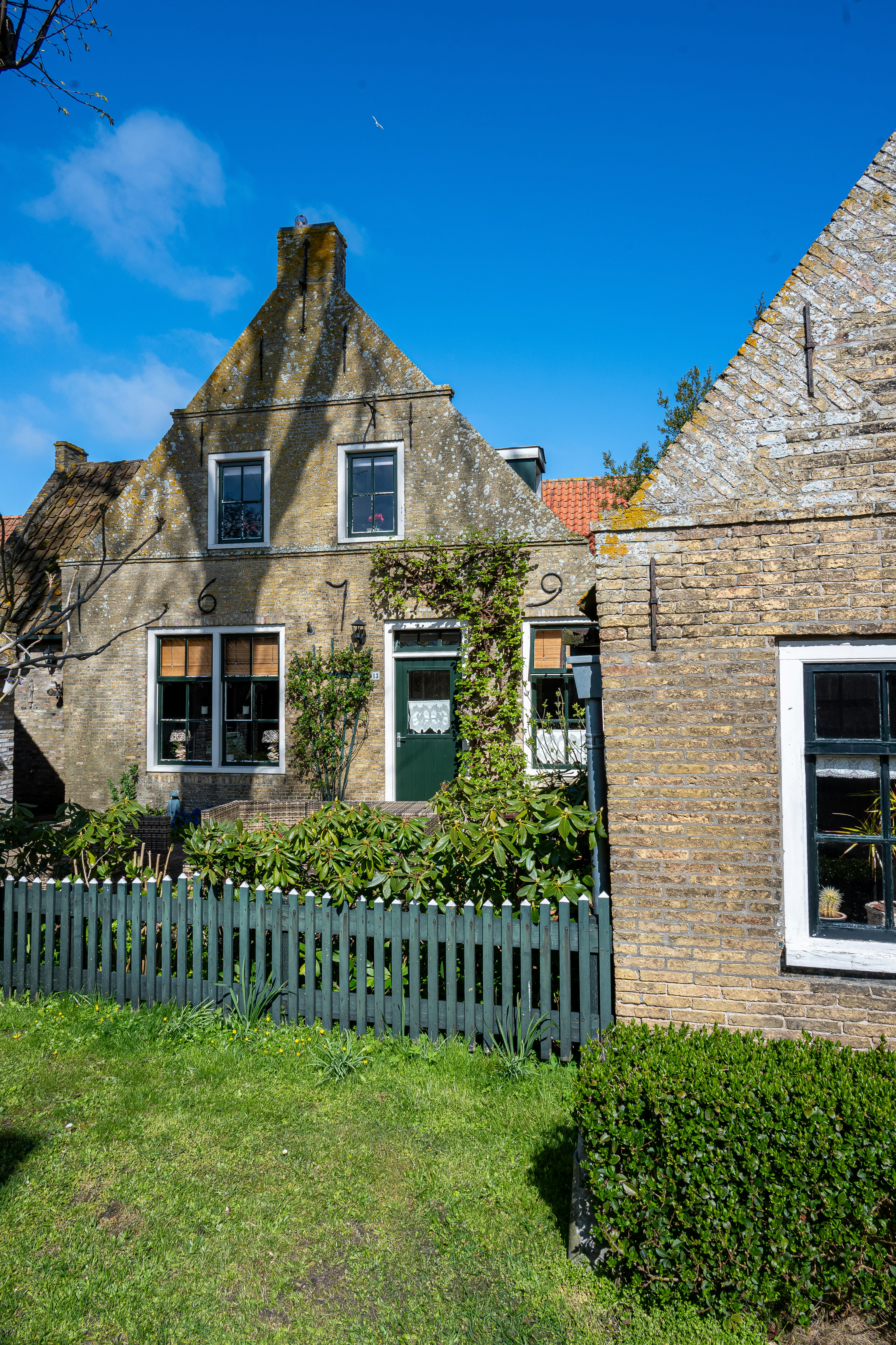 Sunlit Cottage with Ivy-Covered Doorway Under a Bright Blue Sky