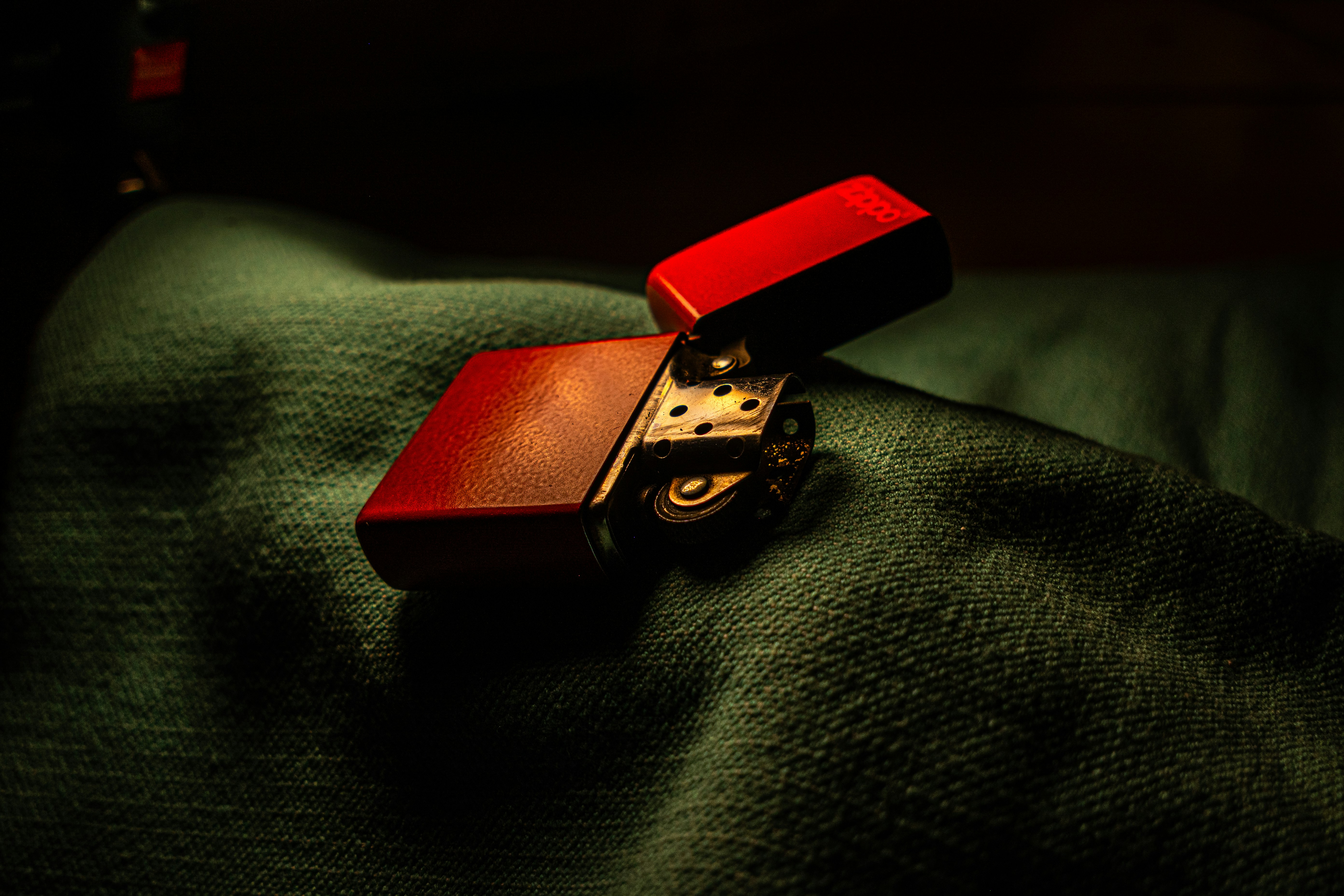 Red Flame, Dark Fabric: A Zippo In Quiet Focus