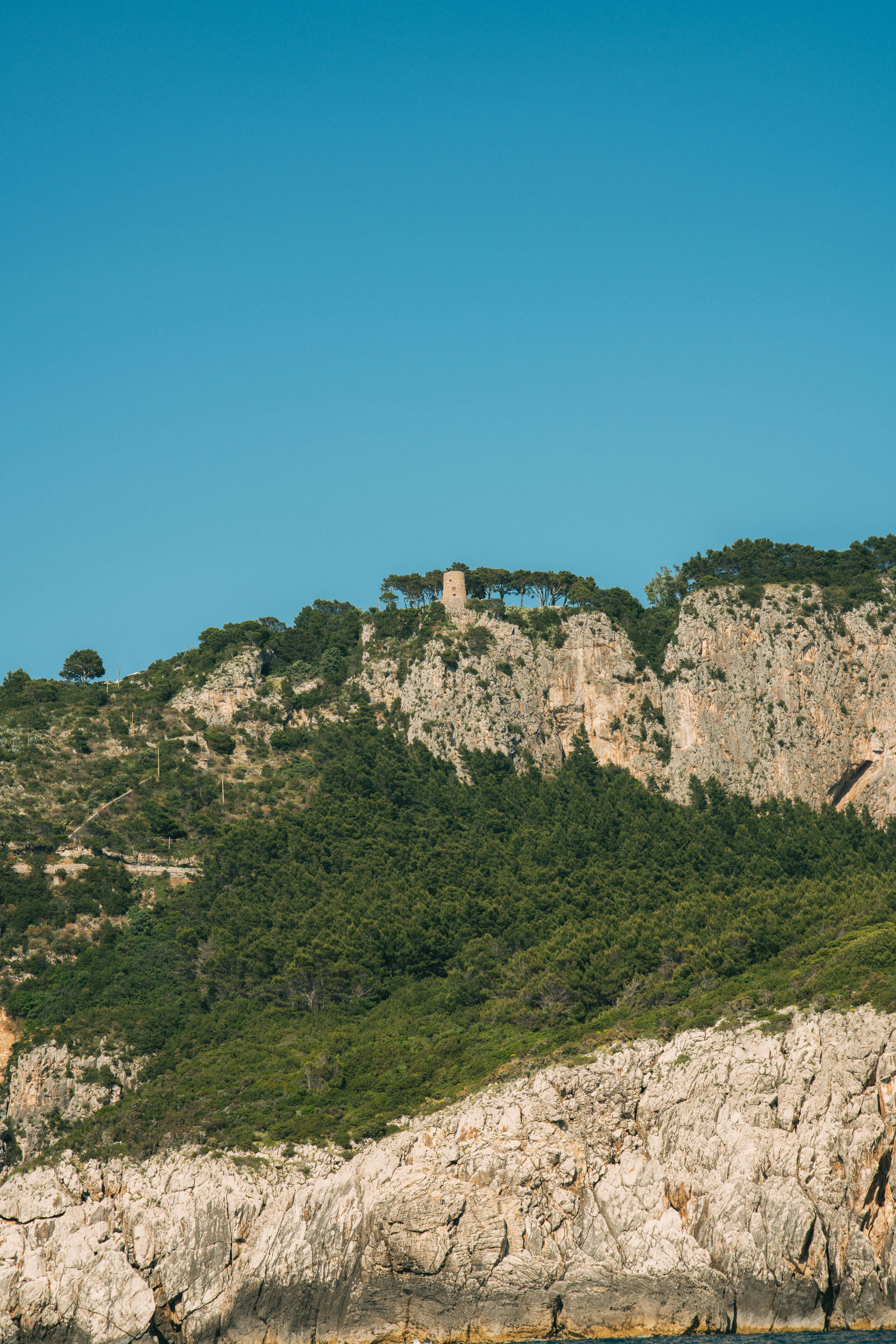 Cliff-top Sentinel: A Rugged Outcrop Under a Quiet Blue Sky