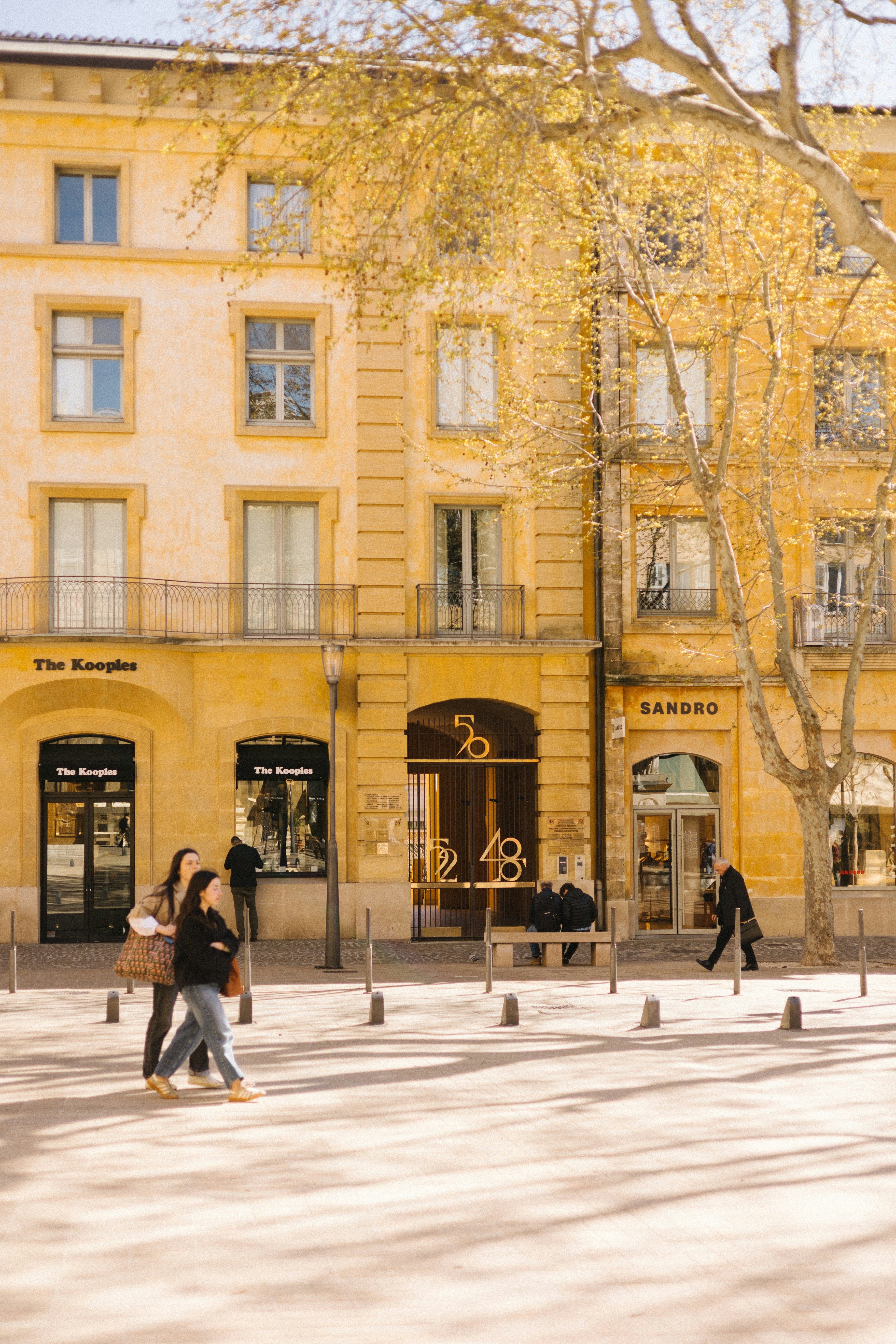 Sunlit Parisian Street: Golden Façade and Moving Pedestrians