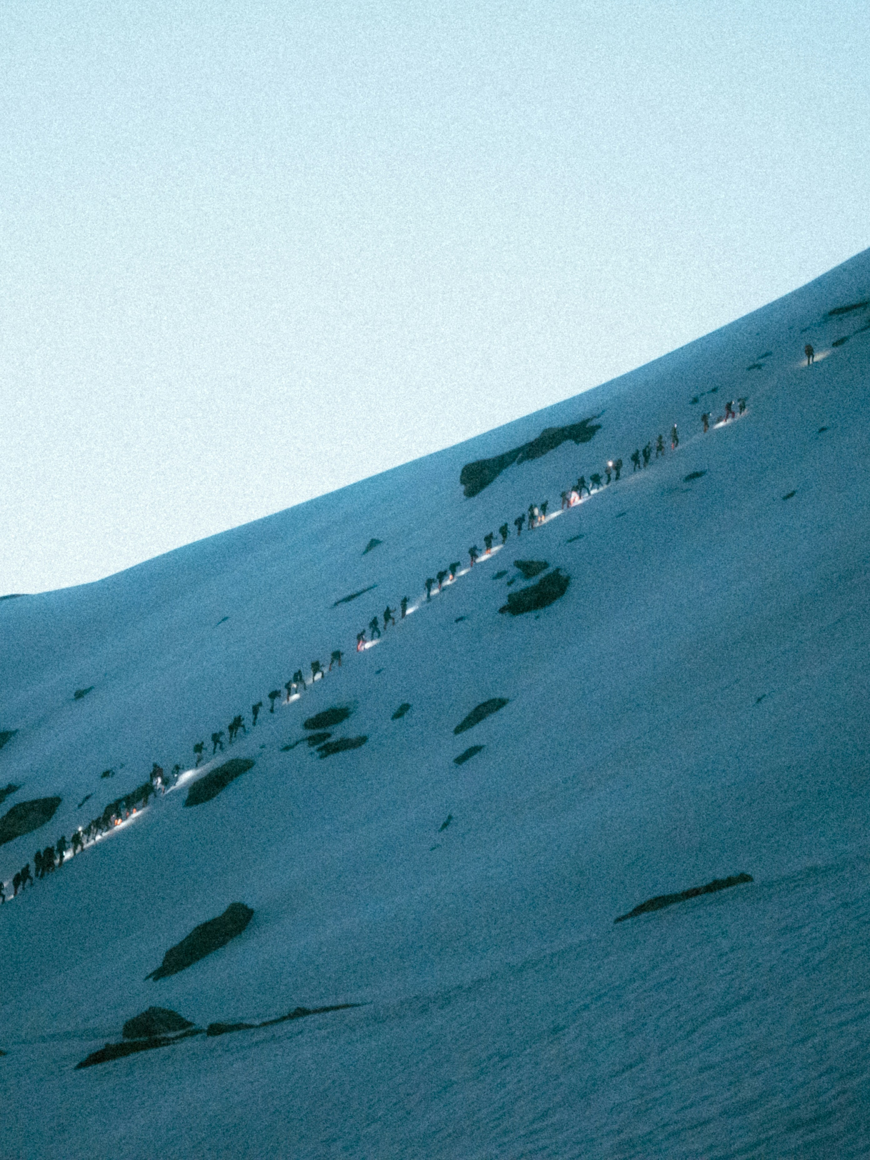 Snowbound Ascent: A Line of Climbers Threading the Mountain