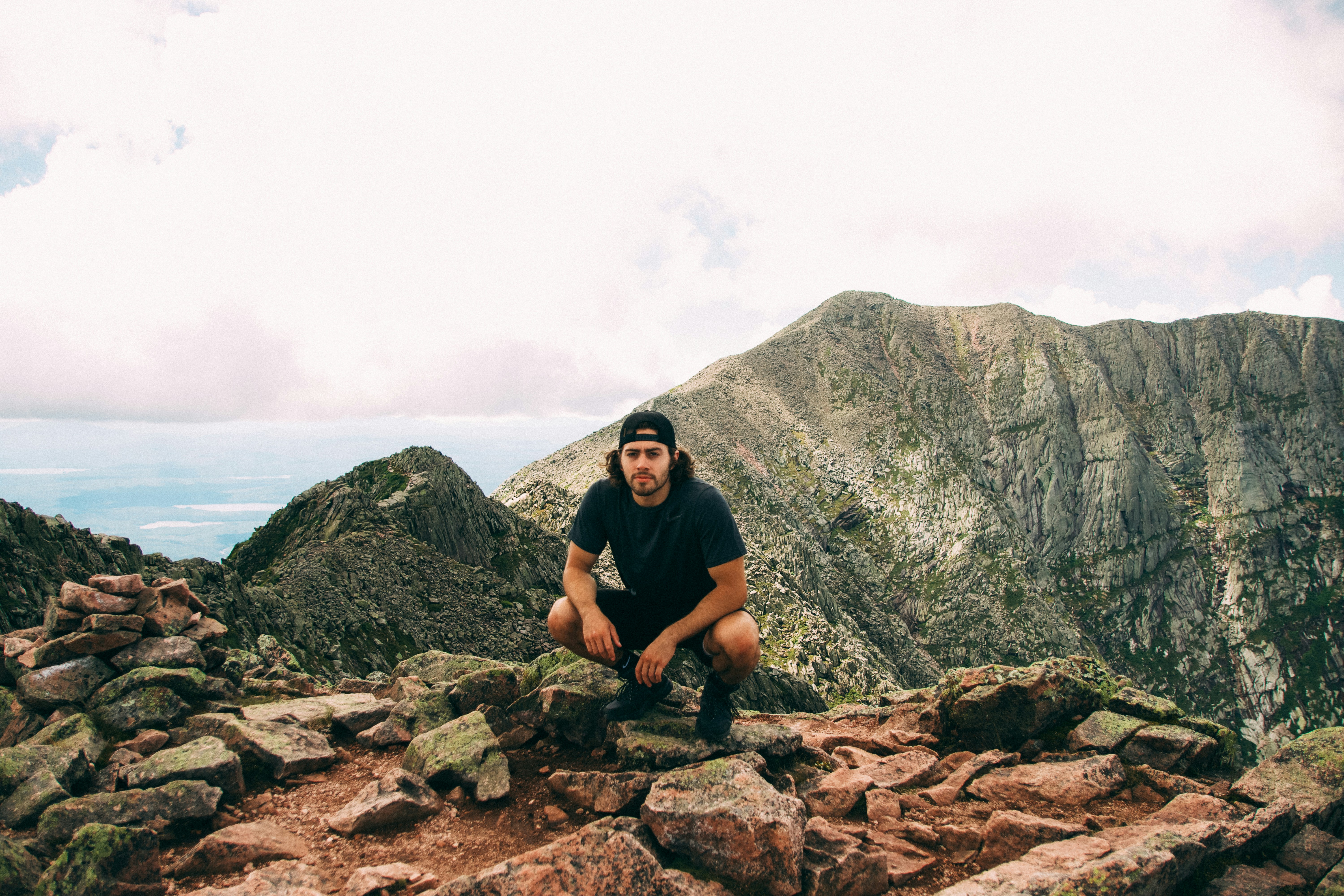 Descent from the Crag: a lone climber pausing on rocky ledges beneath jagged peaks