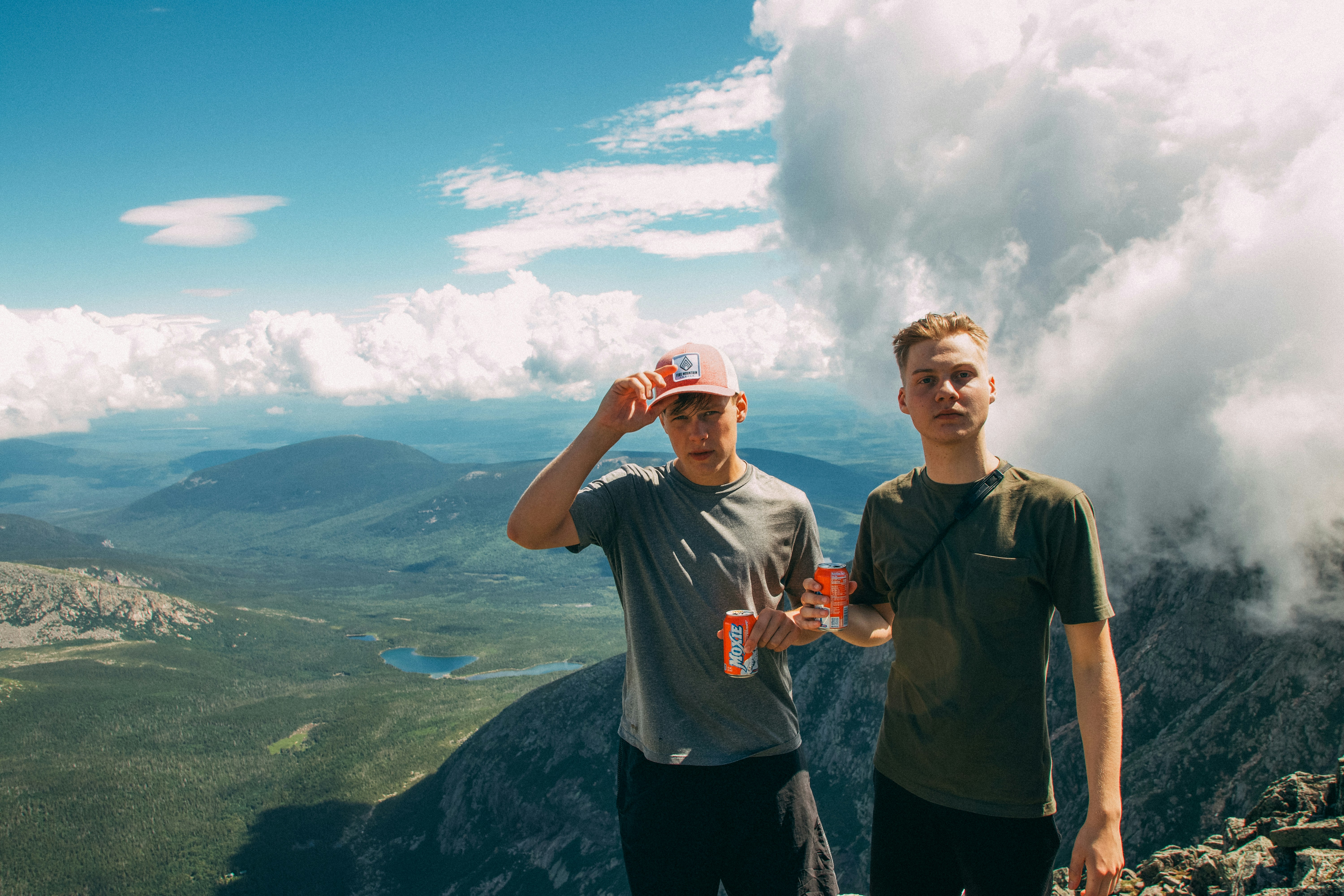 Two hikers toast atop a cloud-kissed ridge with expansive alpine views