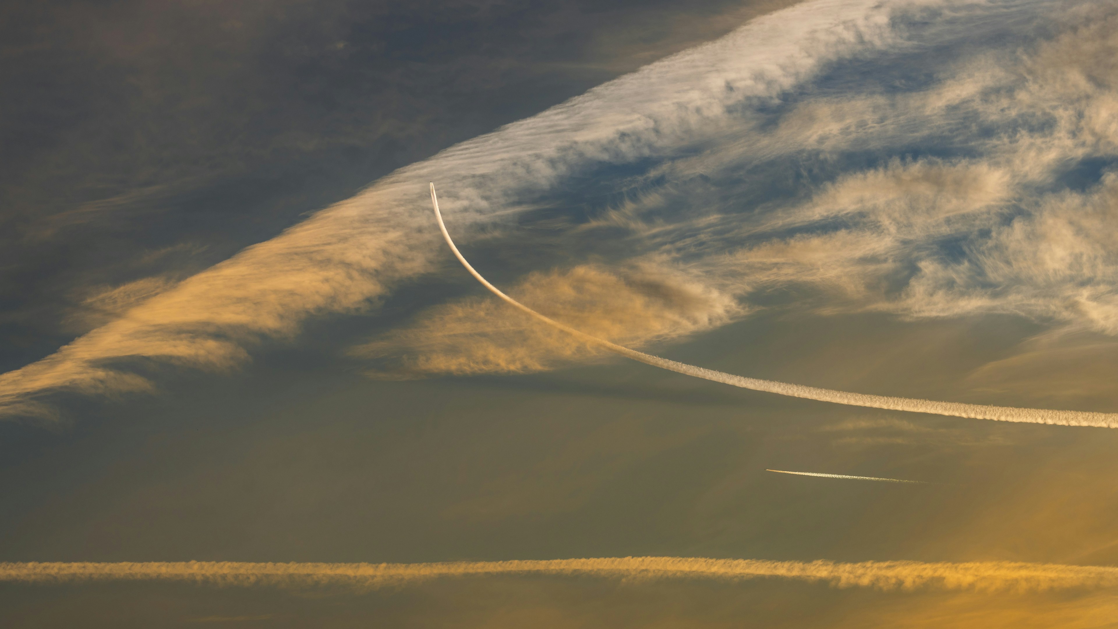 Curved Contrails Across a Dusk Sky
