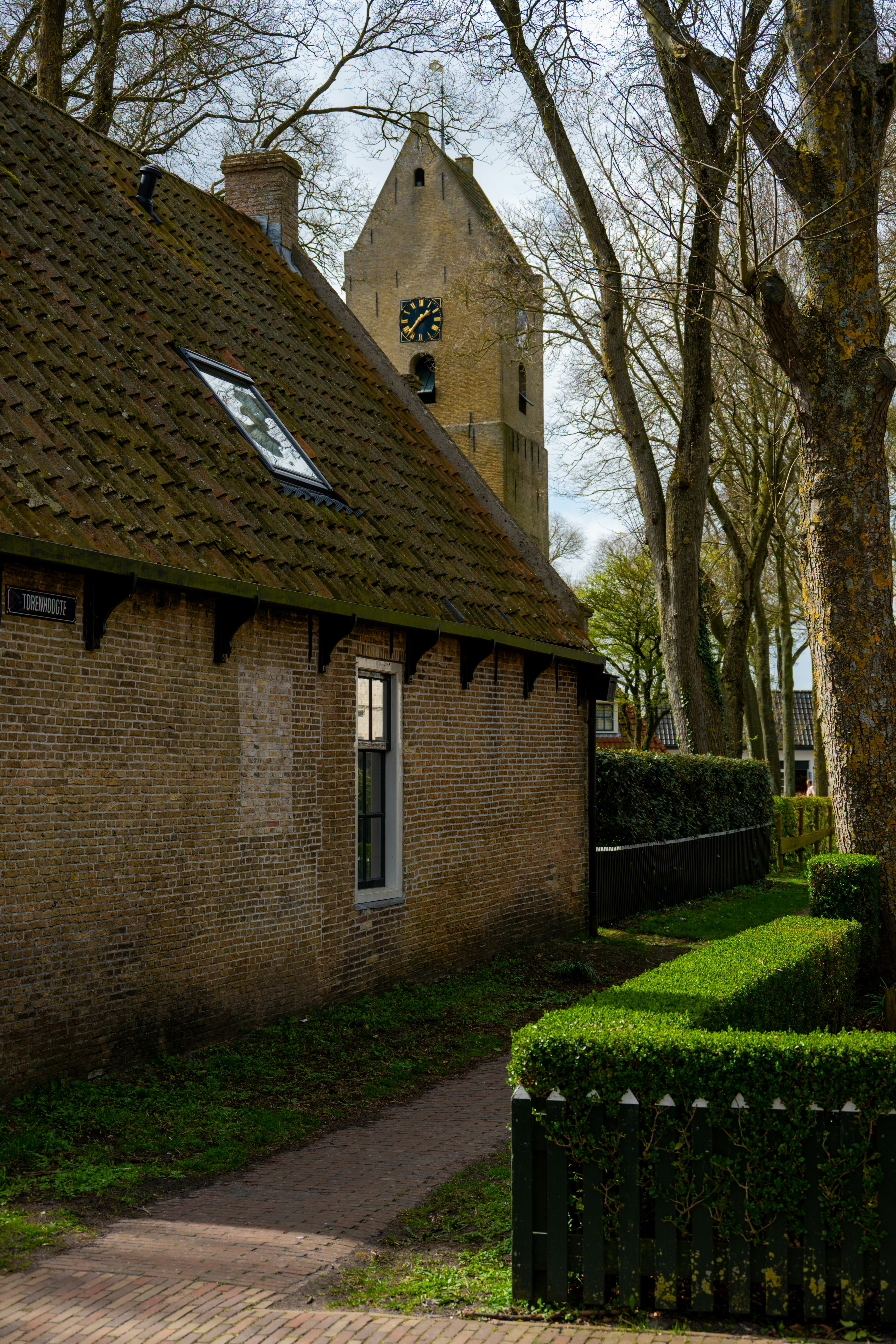 Clocktower Through a Brick Village Wall