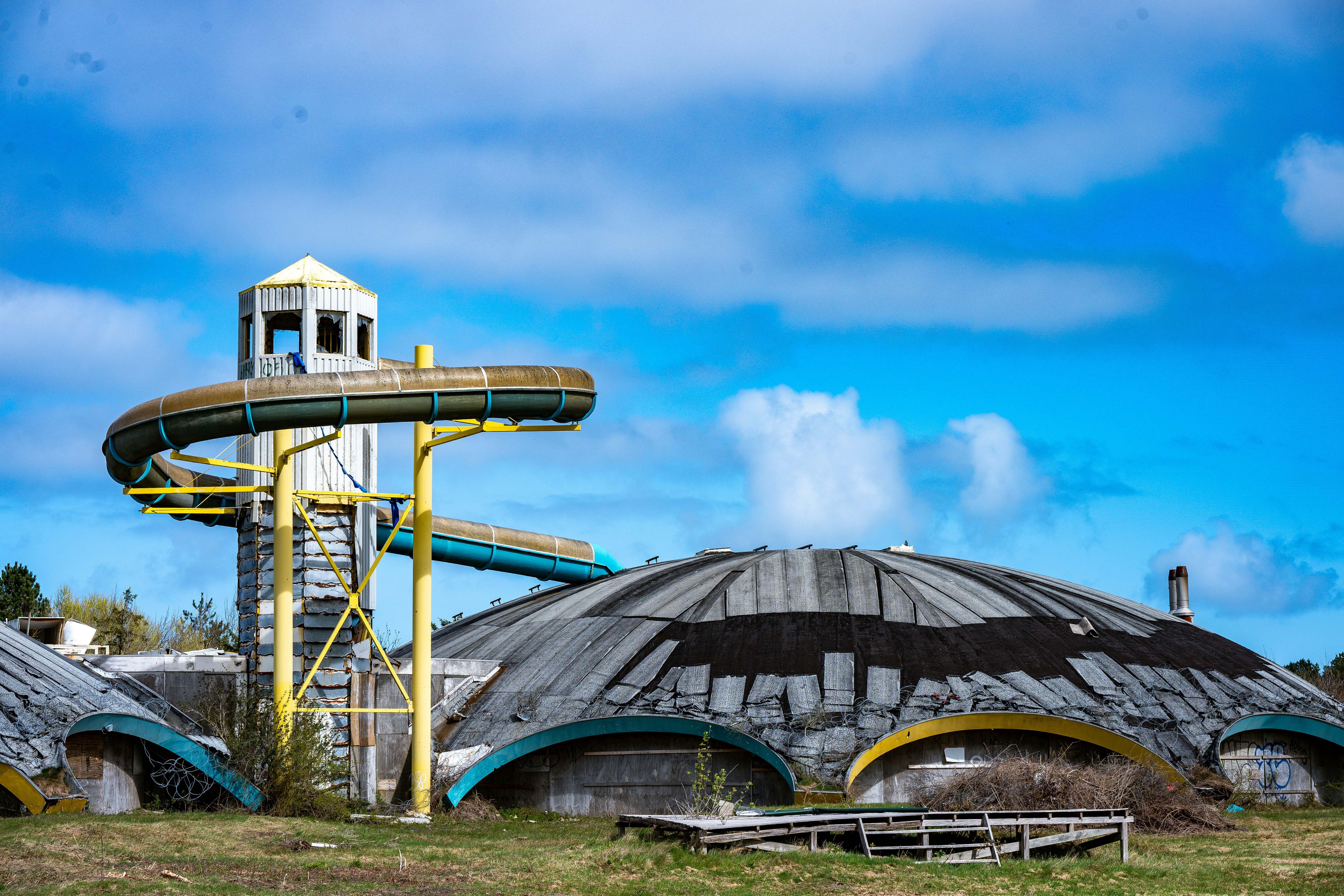 Tilted Waterpark Towers and Aged Dome Roofs Under a Bright Sky