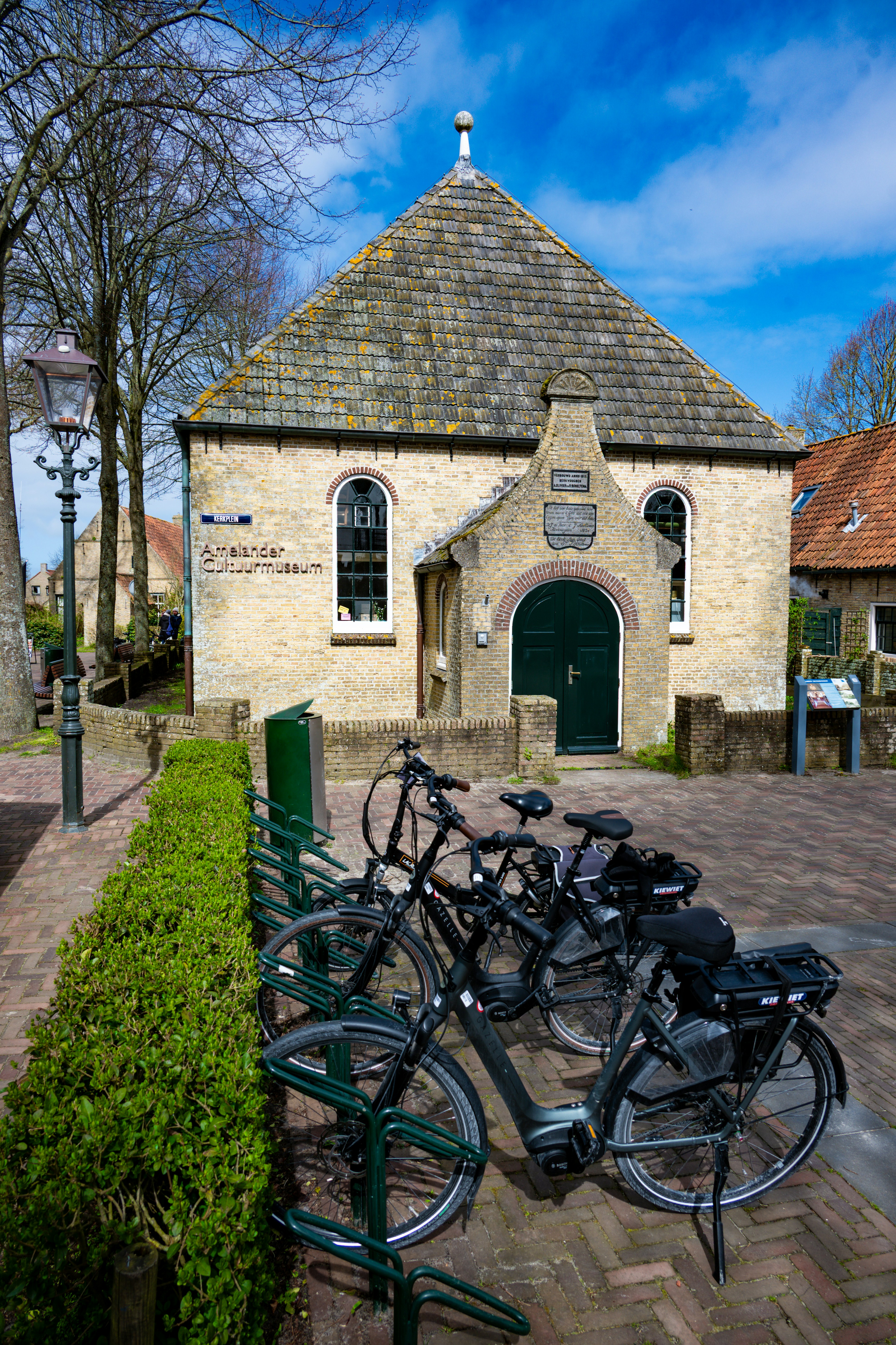 Historic brick pavilion with bicycle rack in a sunlit Dutch village square