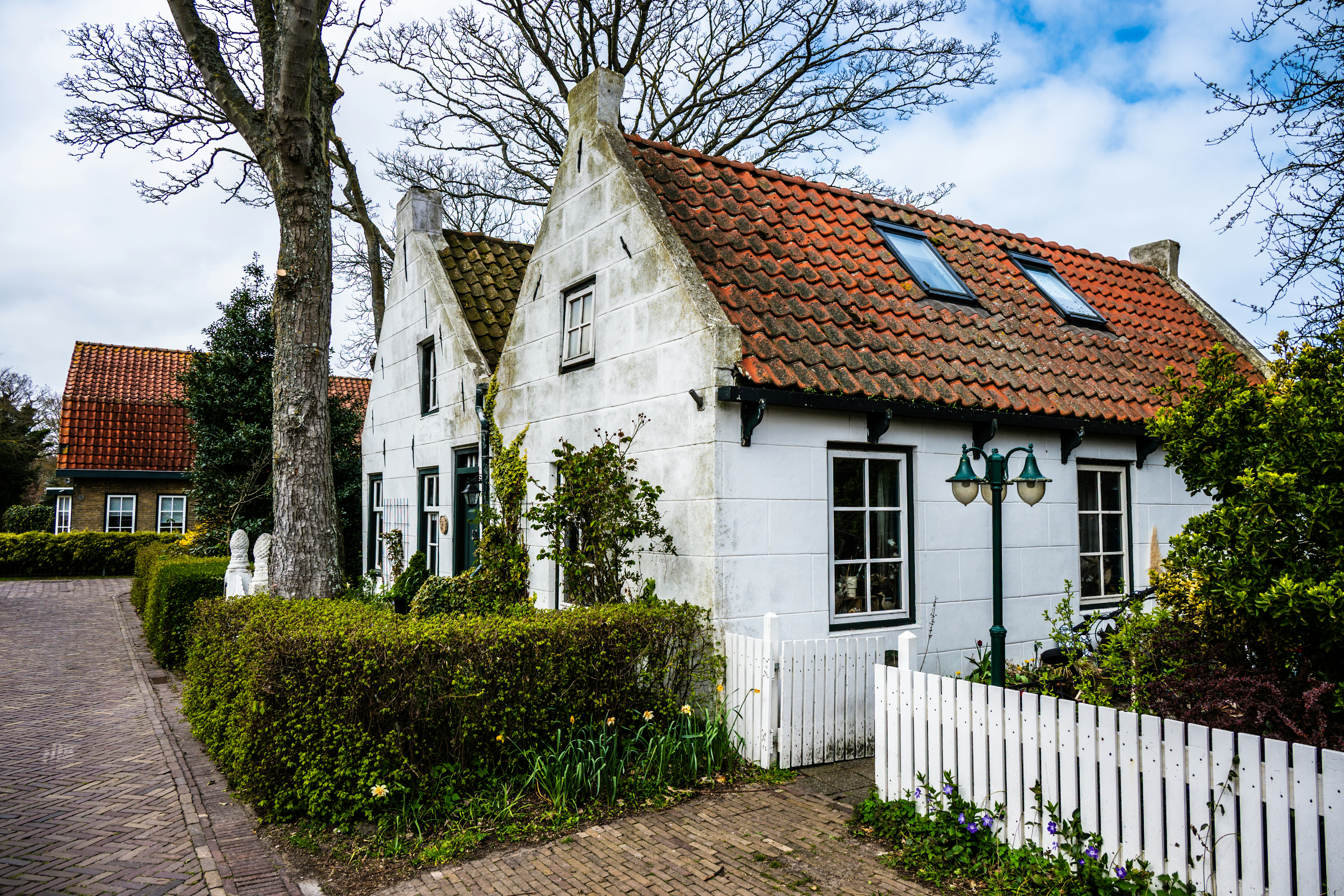 Cottage Row: Whitewashed Homes with Crimson Roofs Along a Brick Walk