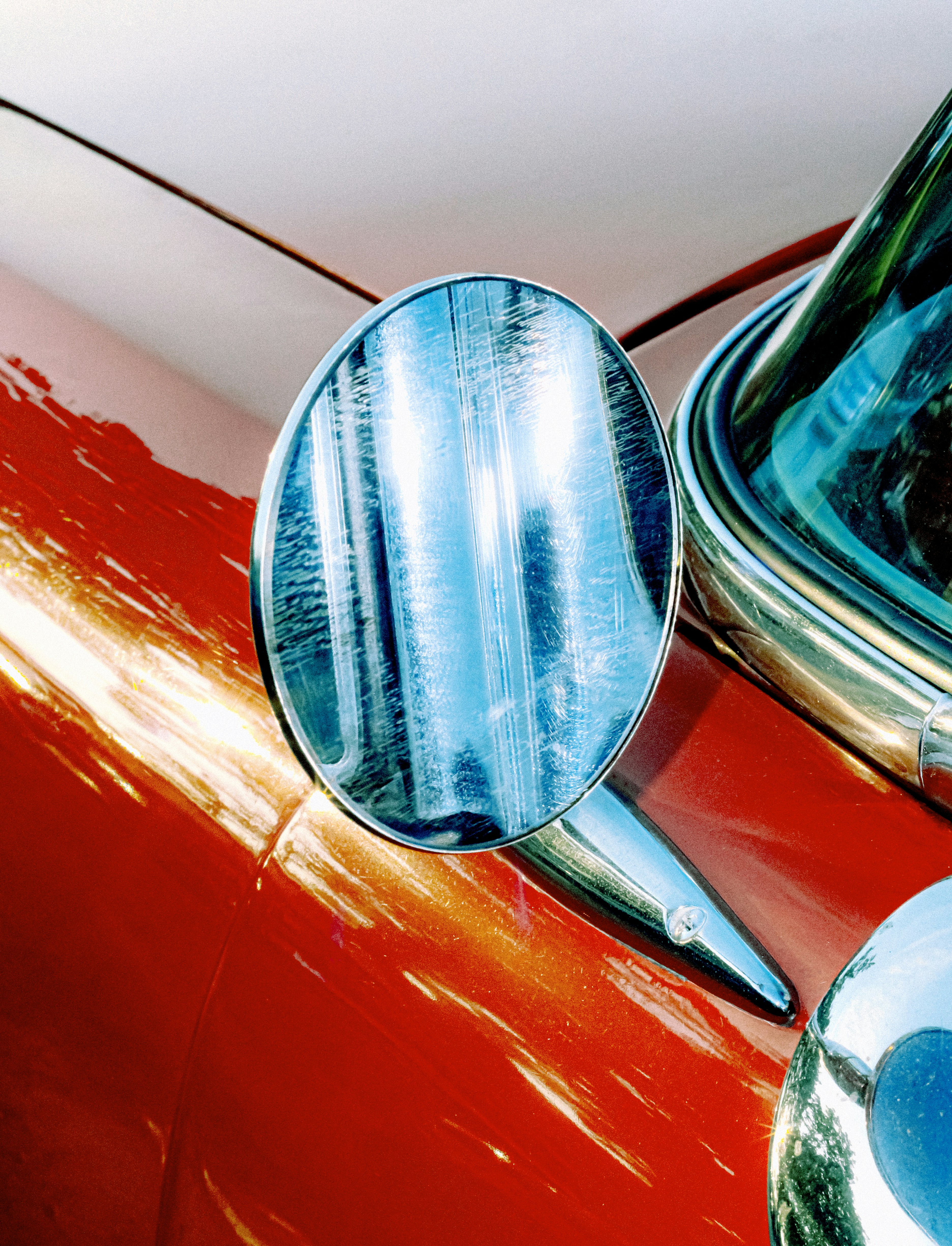 Mirror and chrome on a vintage red car flare with teal glass