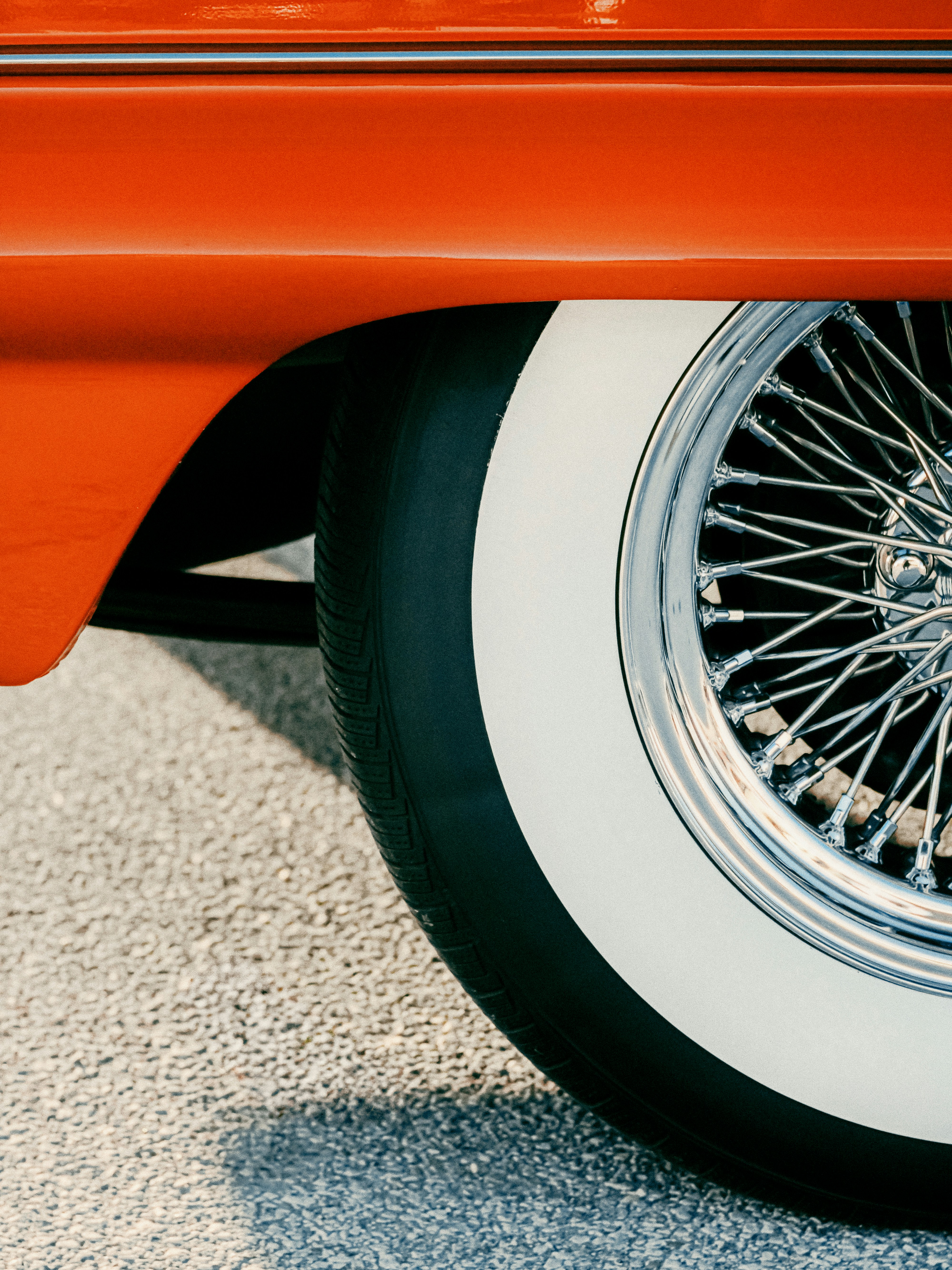 Chrome spokes and bold orange trail: a classic car wheel portrait
