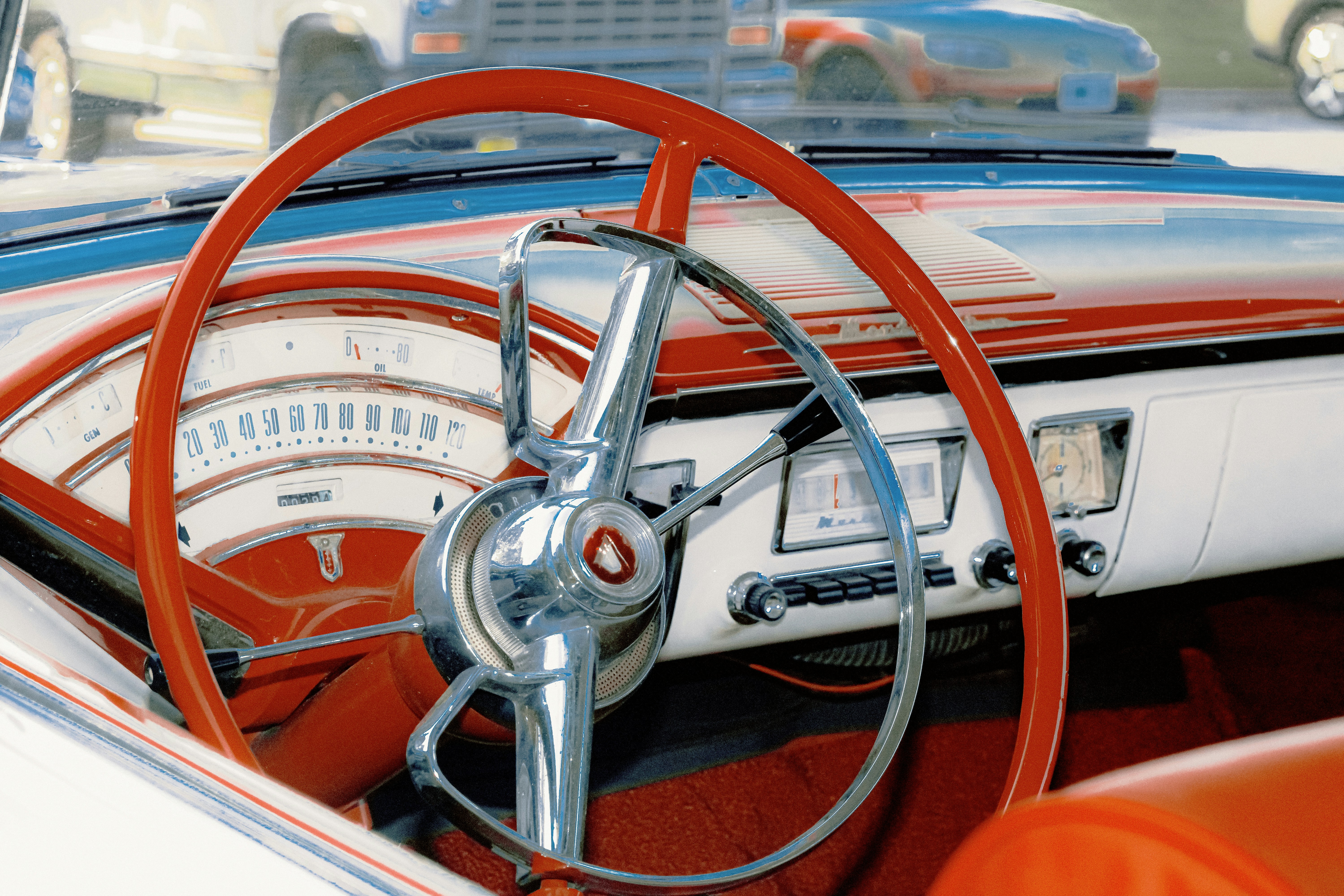 Red steering wheel and chrome dash: a glimpse into a classic car's cockpit