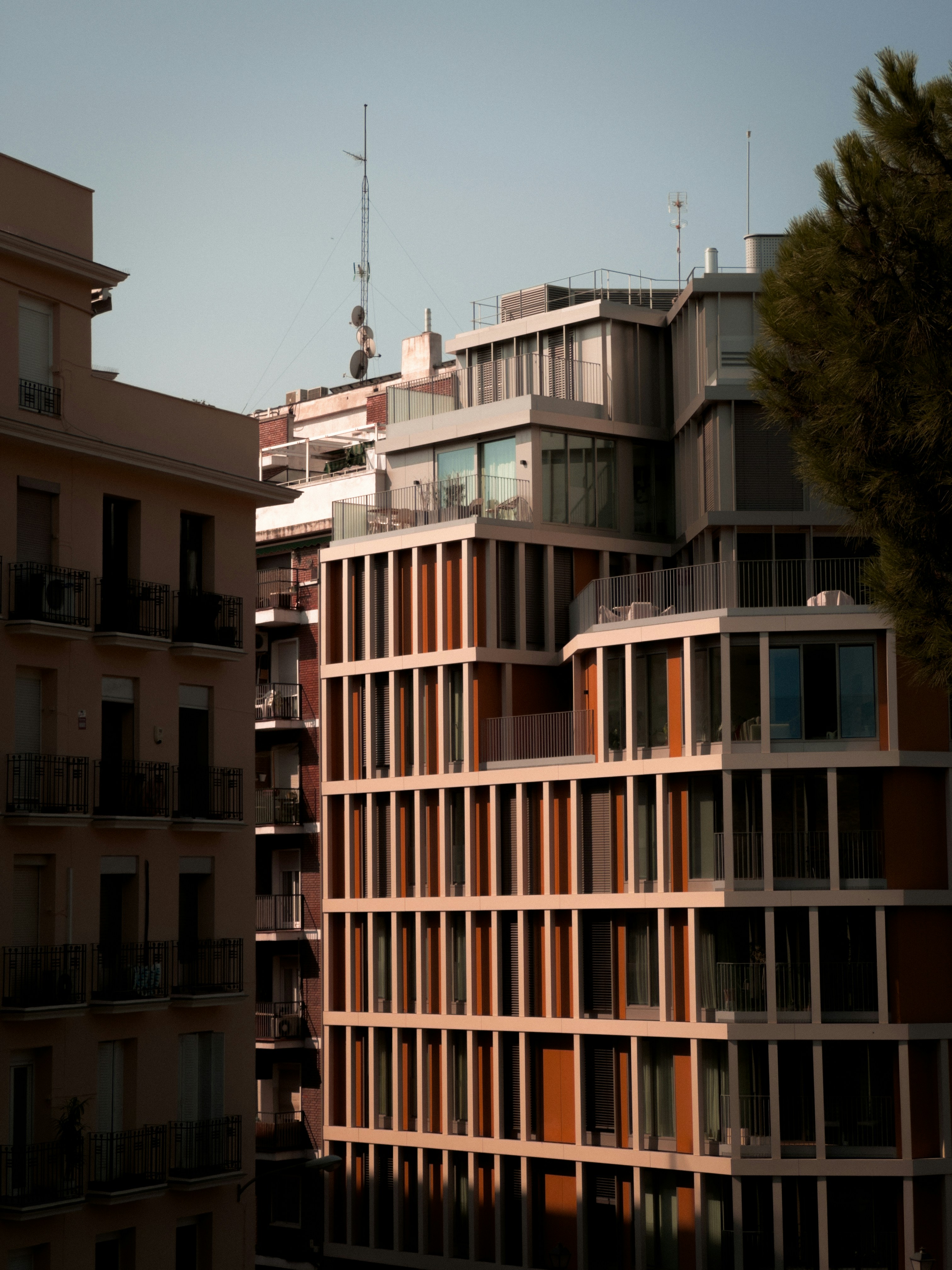 Sunlit Facade Rhythm: Modern Balcony Towers Rising in Narrow Street