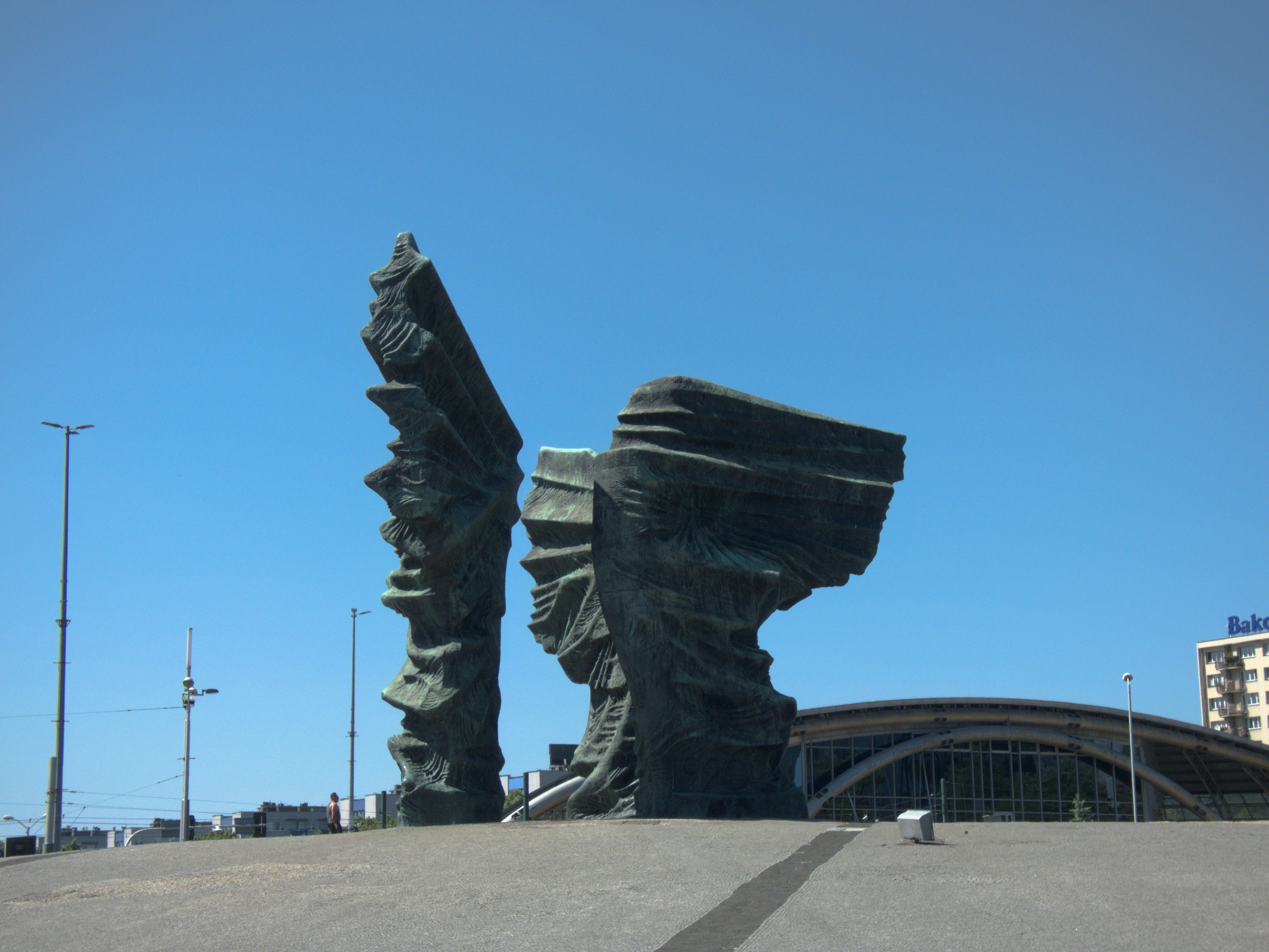 Winged sculpture at the city harbor plaza under a clear blue sky